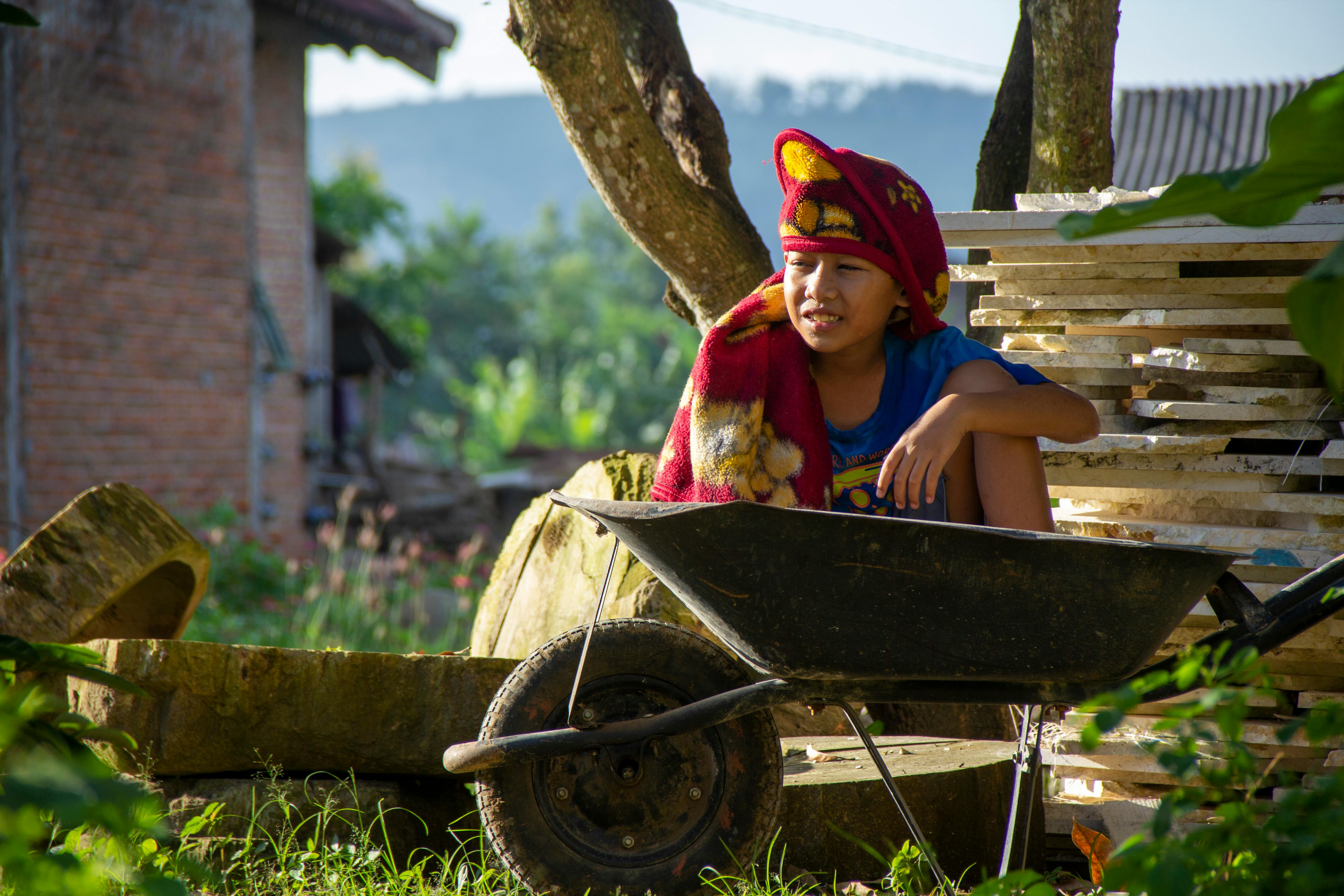 Child Sitting in a Wheelbarrow · Free Stock Photo