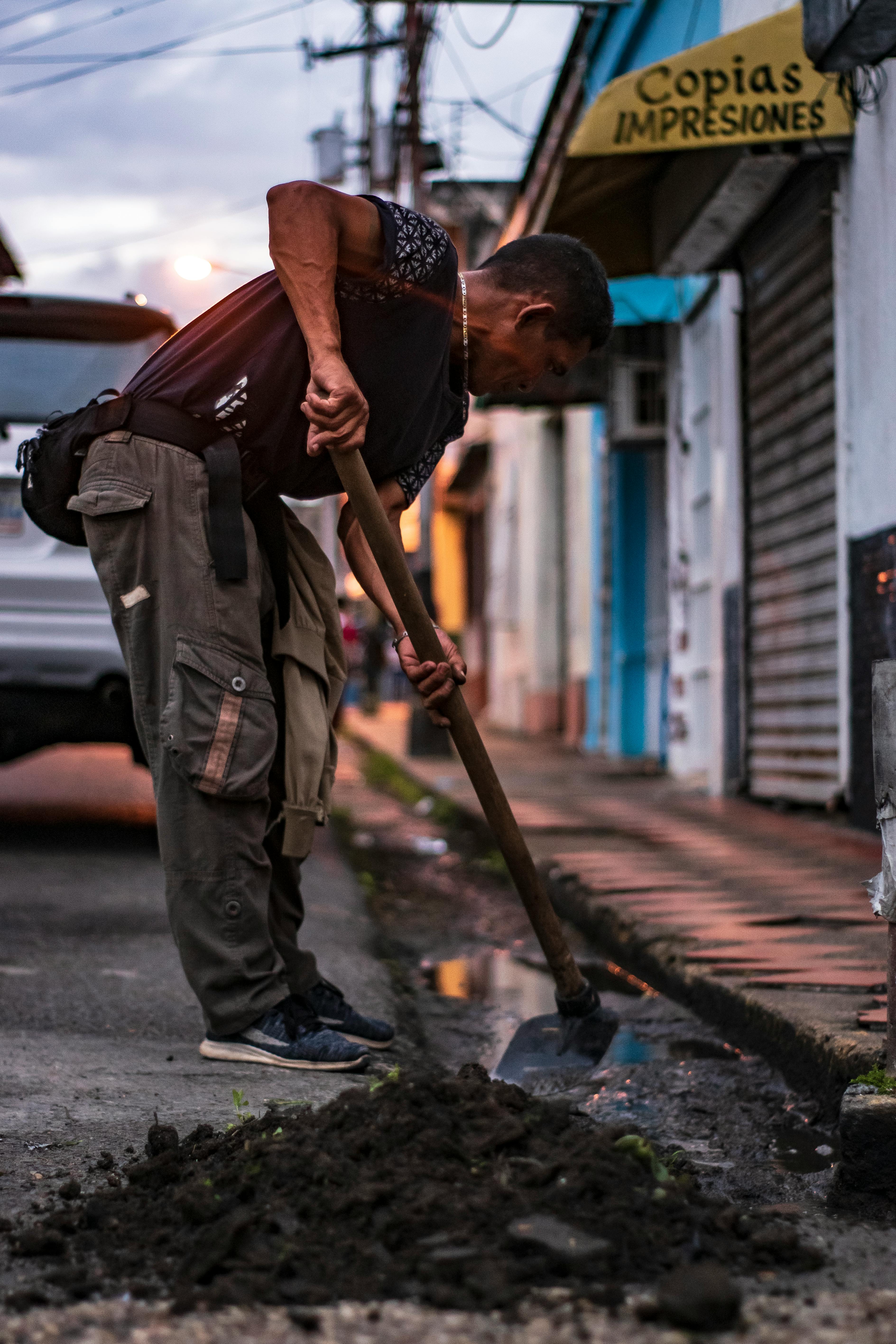Man Using a Shovel to Repair a Hole in the Road · Free Stock Photo