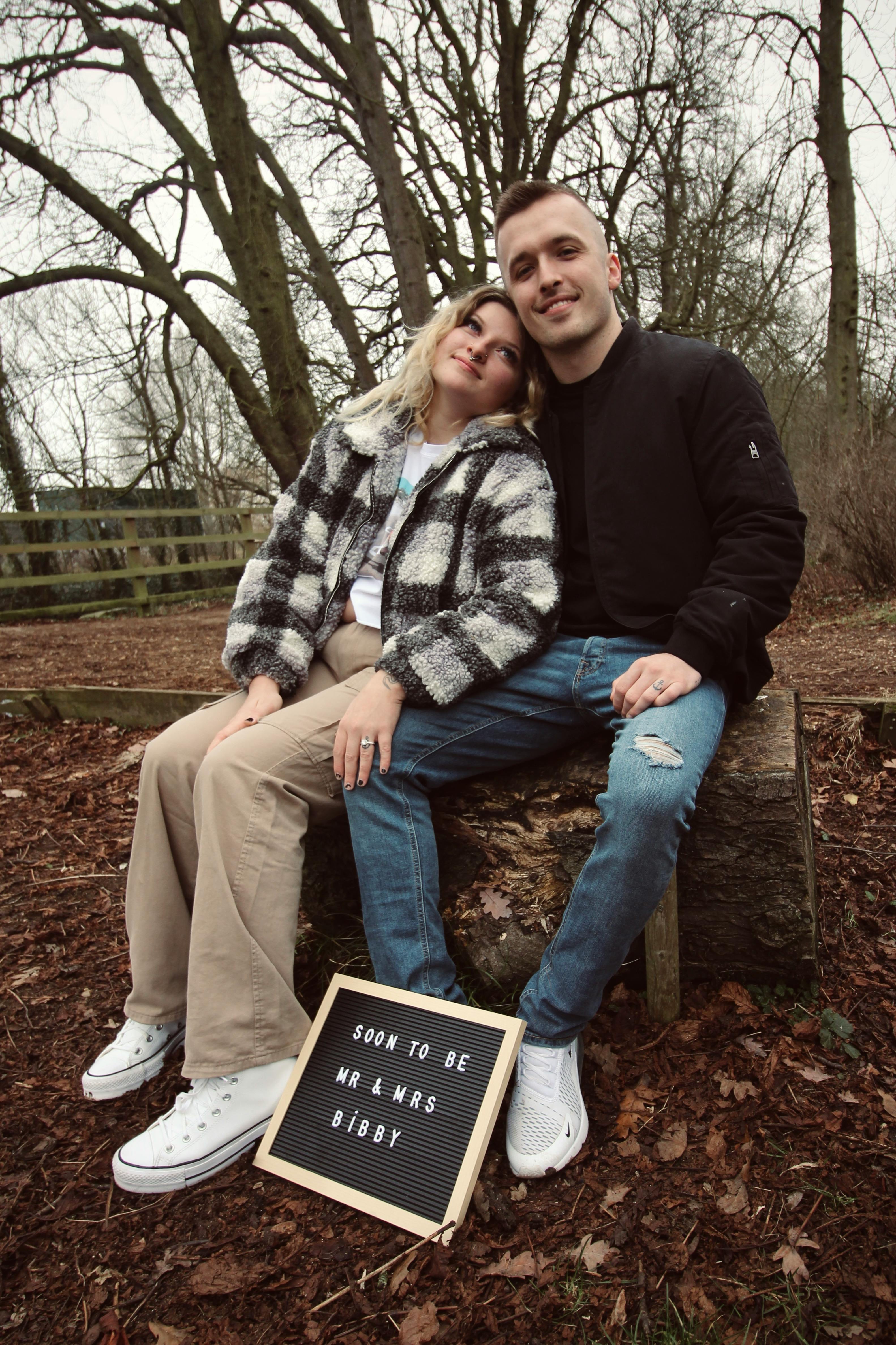 Smiling Couple Sitting on Stump · Free Stock Photo