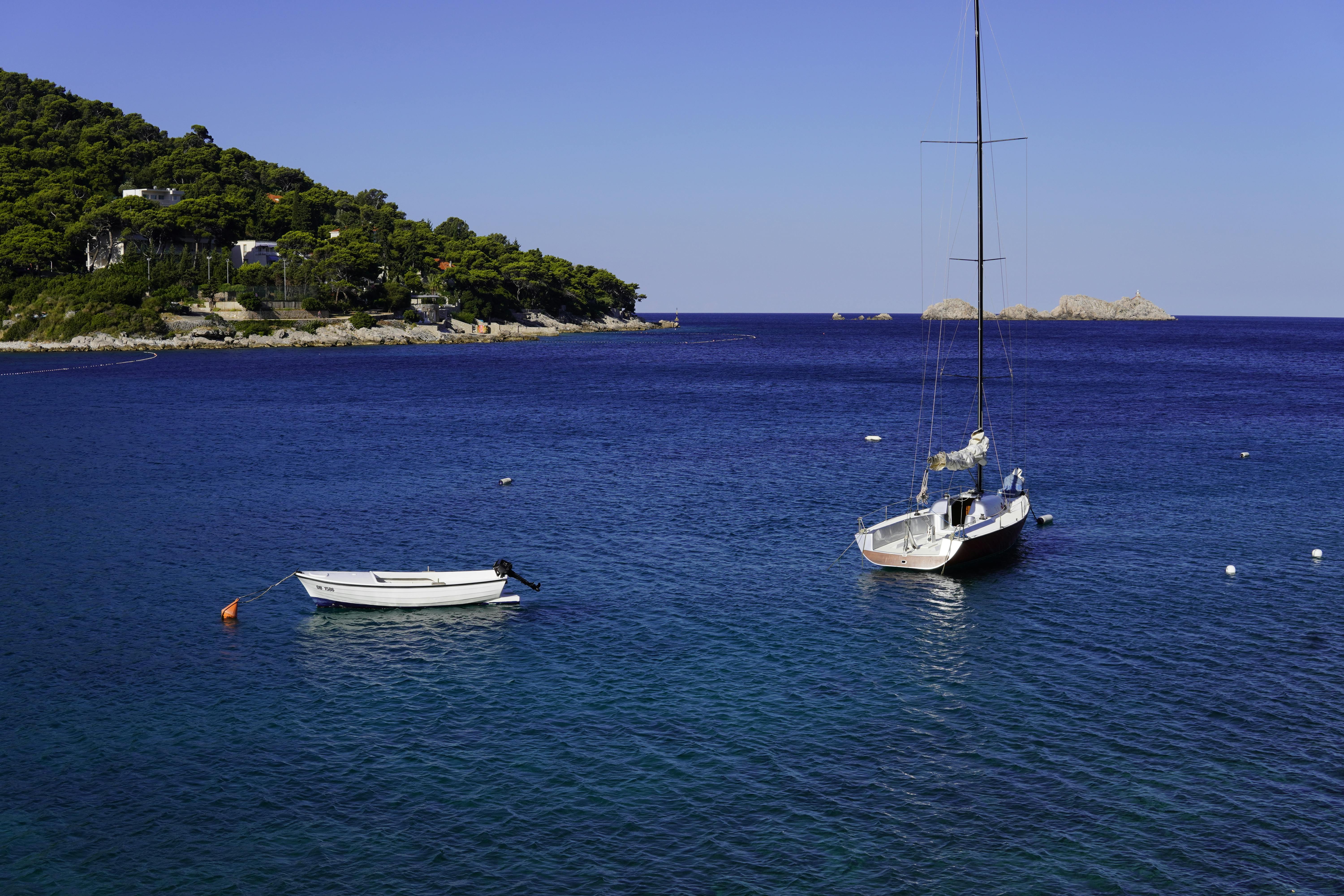 Sailboat and Empty Motorboat on Sea Shore · Free Stock Photo