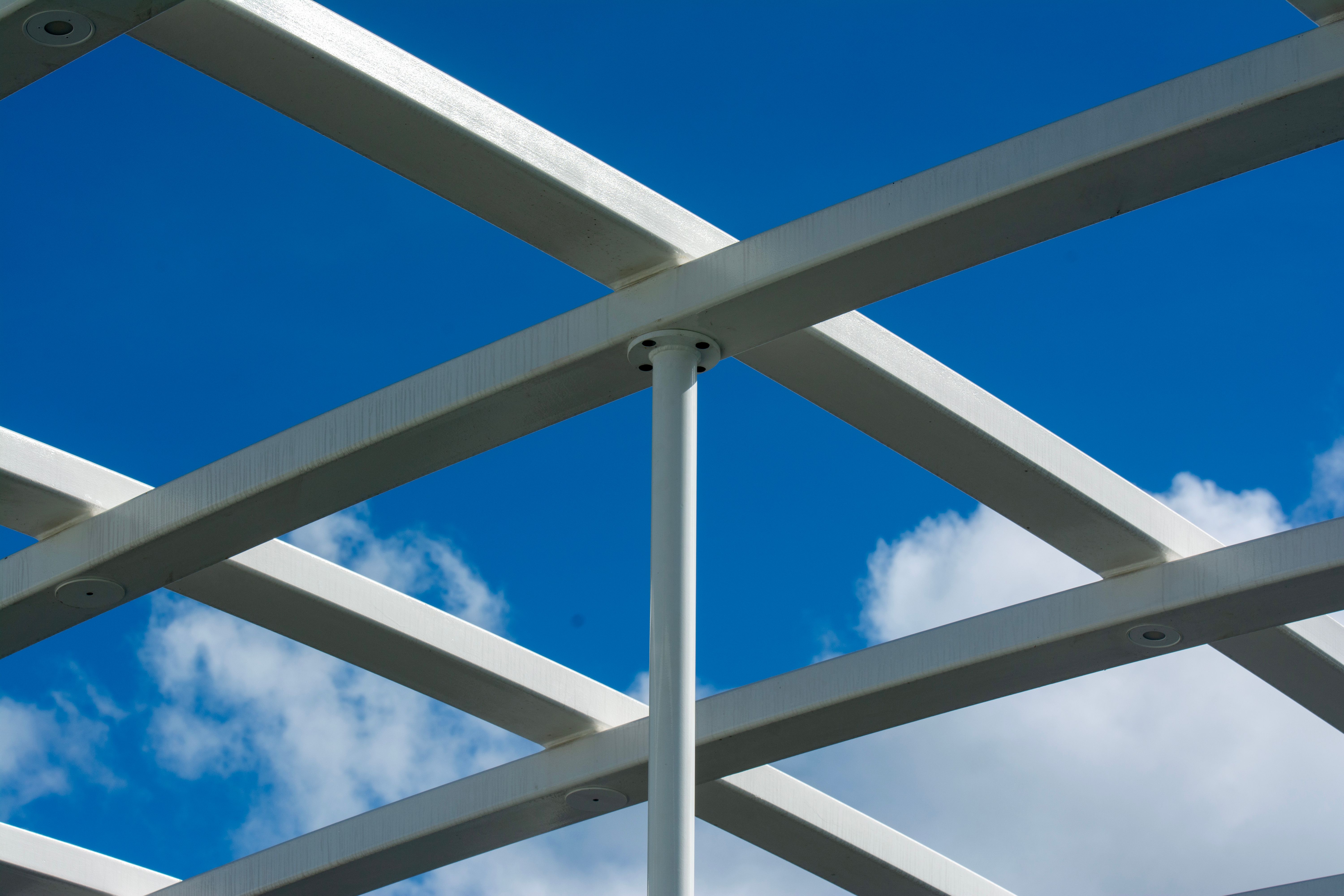 A metal structure with white beams and blue sky · Free Stock Photo