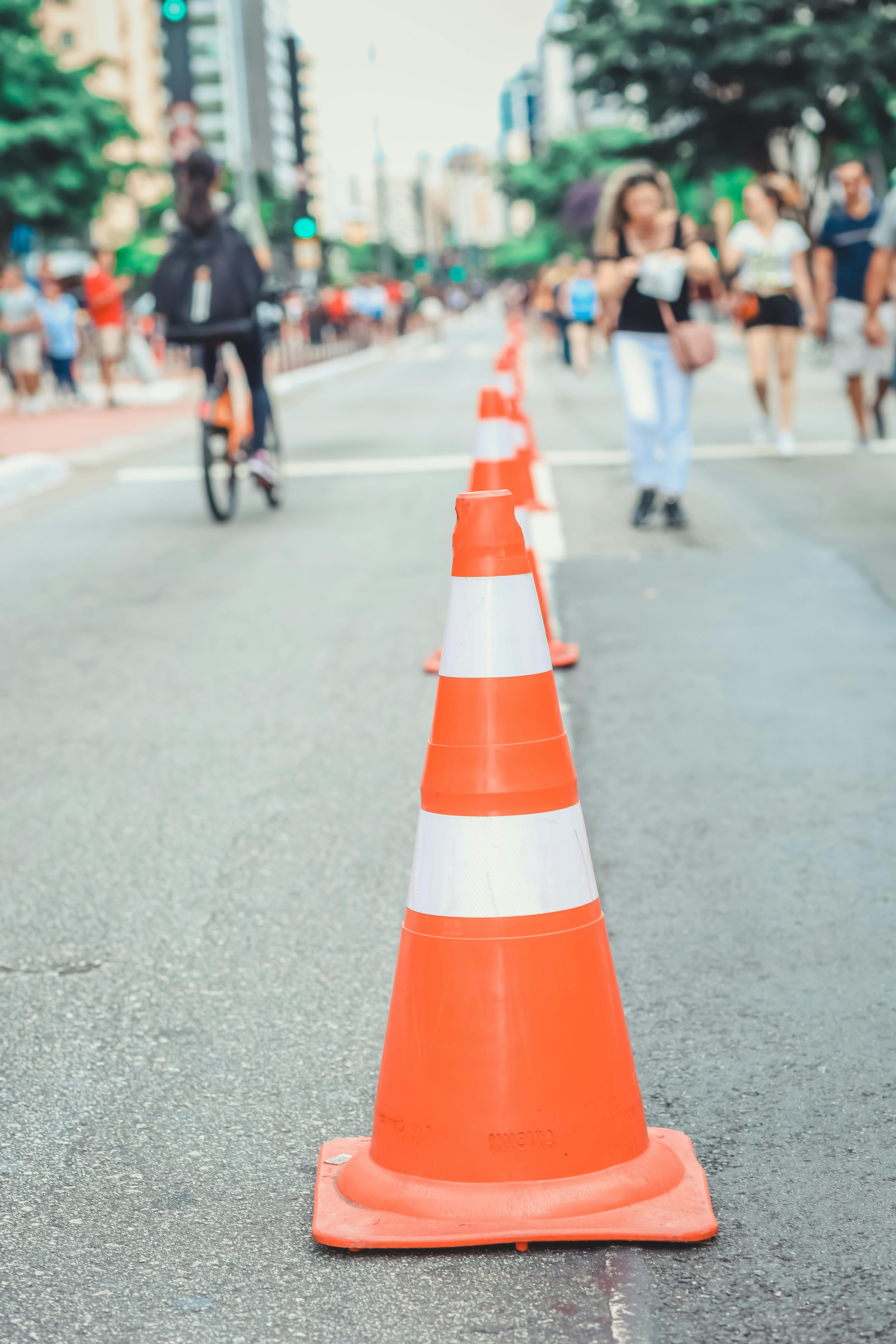 Close-up of a Row of Traffic Cones on a Street with People Running in a ...