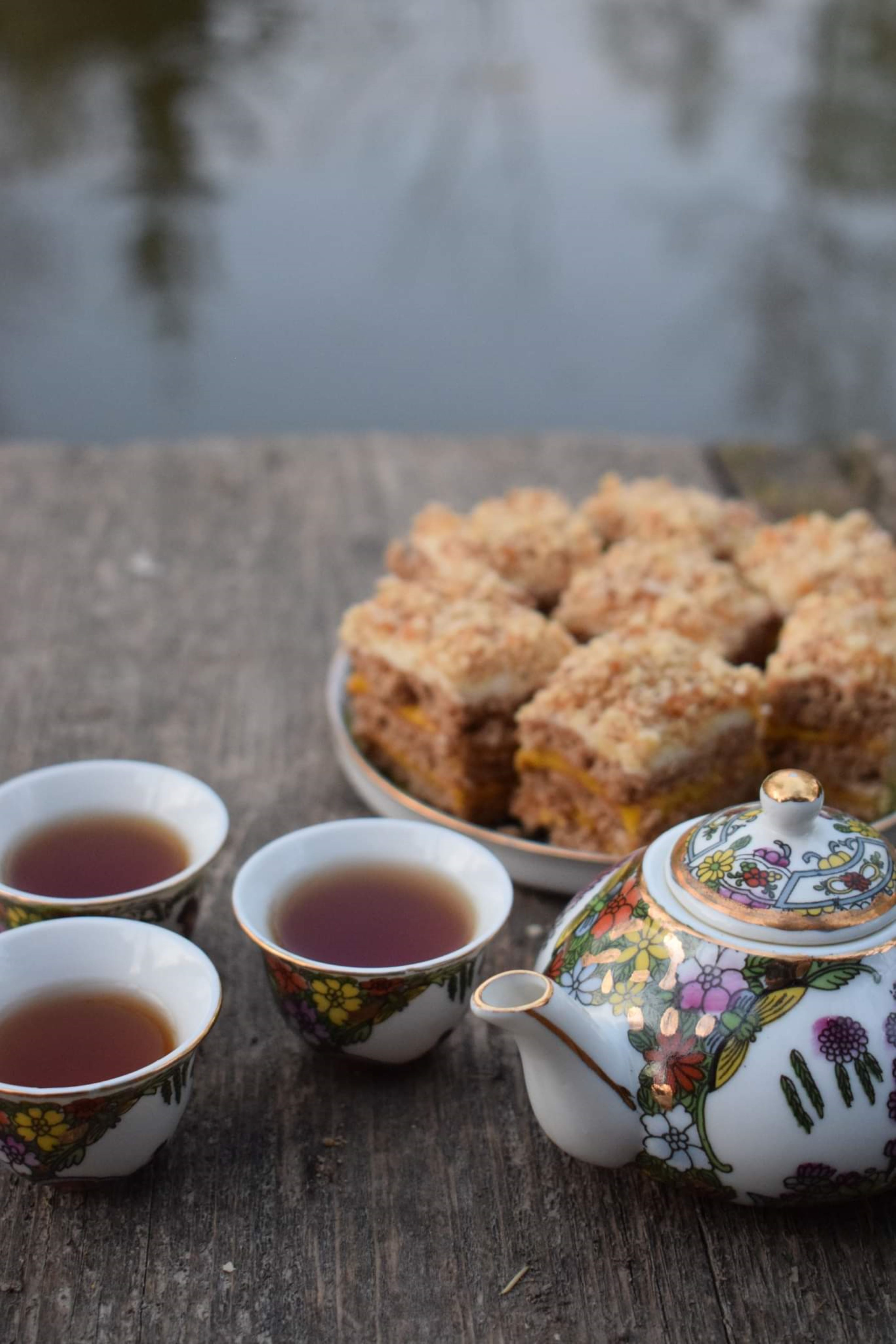 Tea and cakes on a table next to a lake · Free Stock Photo