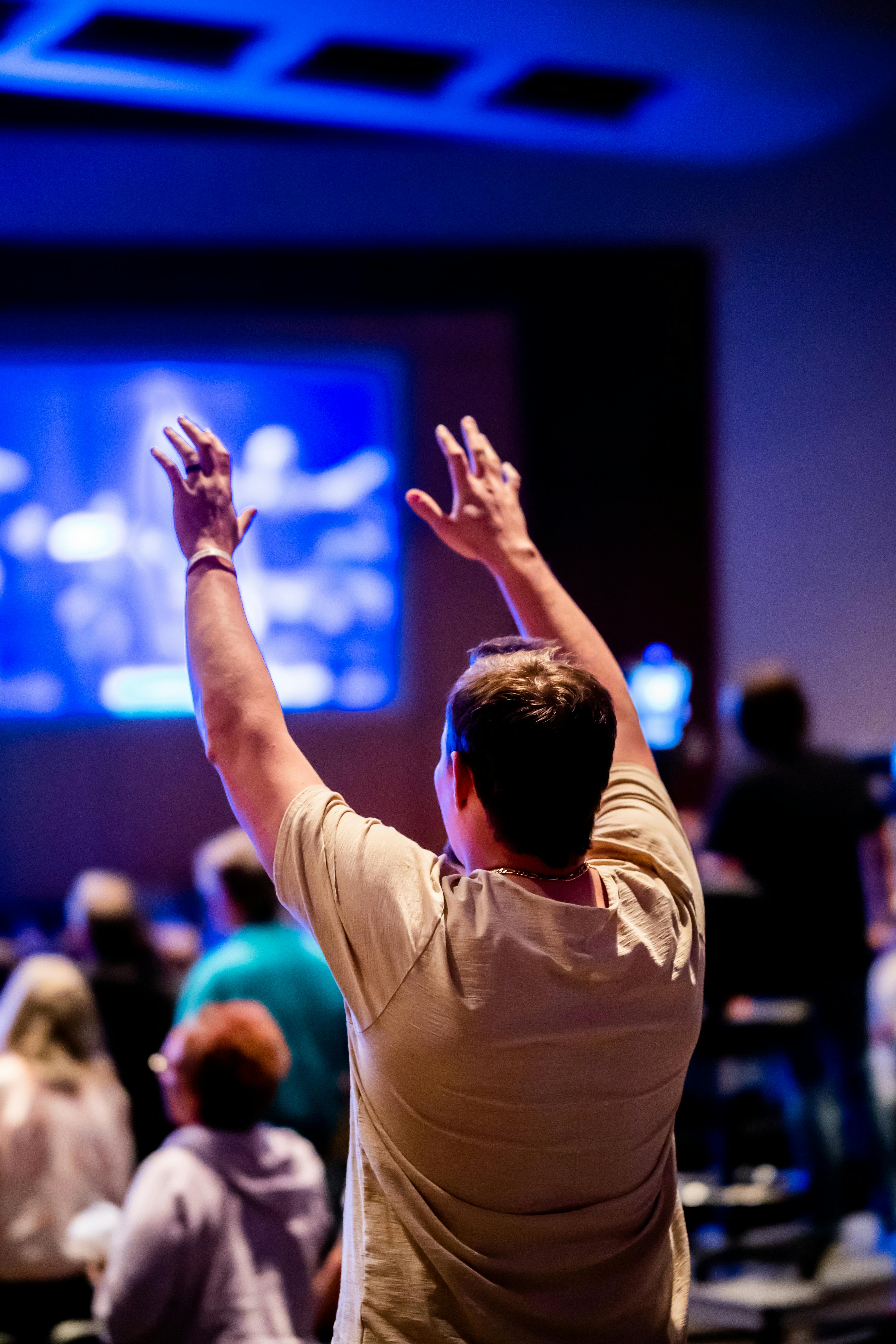 Photo of a Man Raising his Hands towards a Stage with a Cross · Free ...