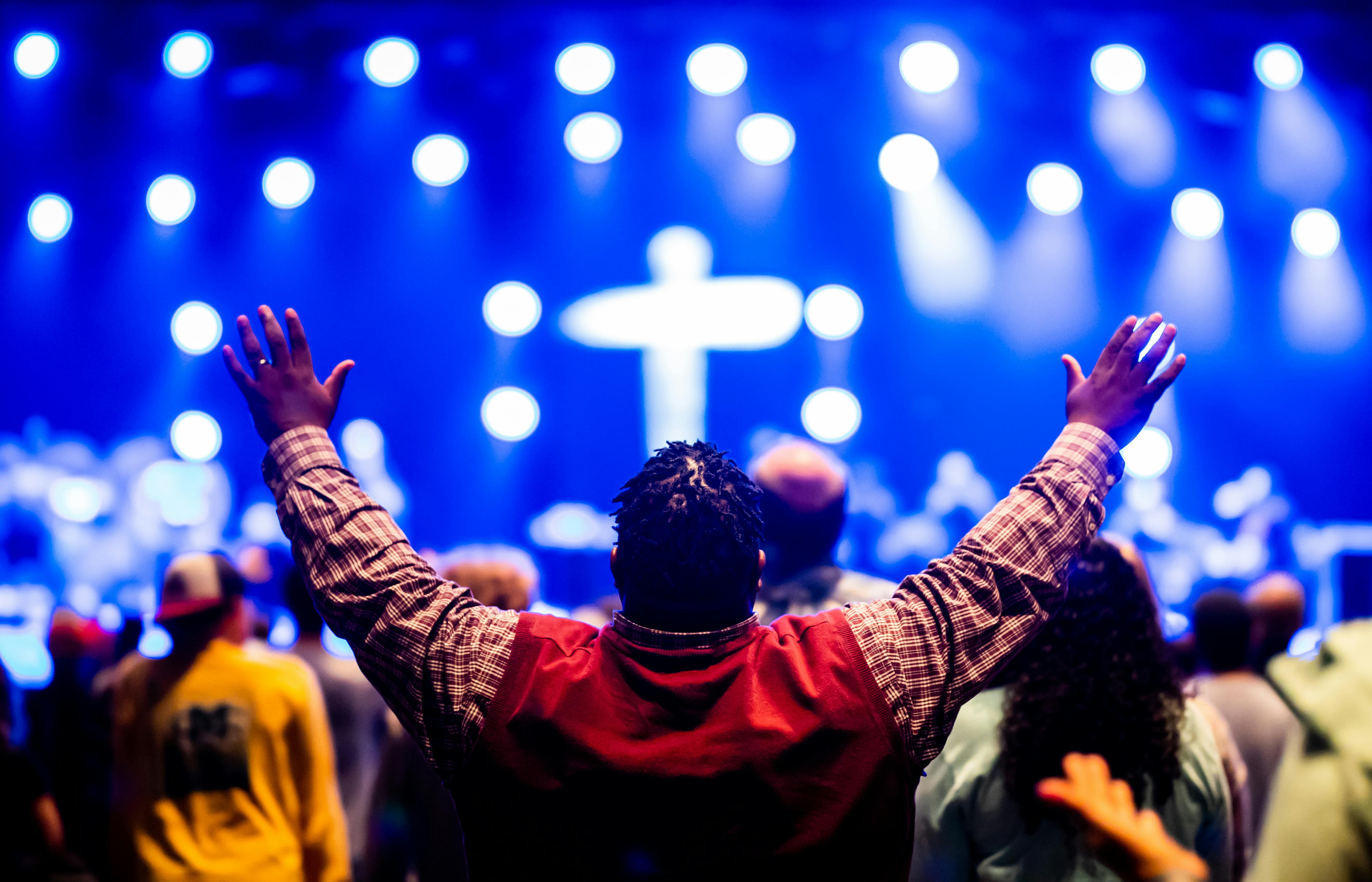 Photo of a Man Raising his Hands towards a Stage with a Cross · Free ...