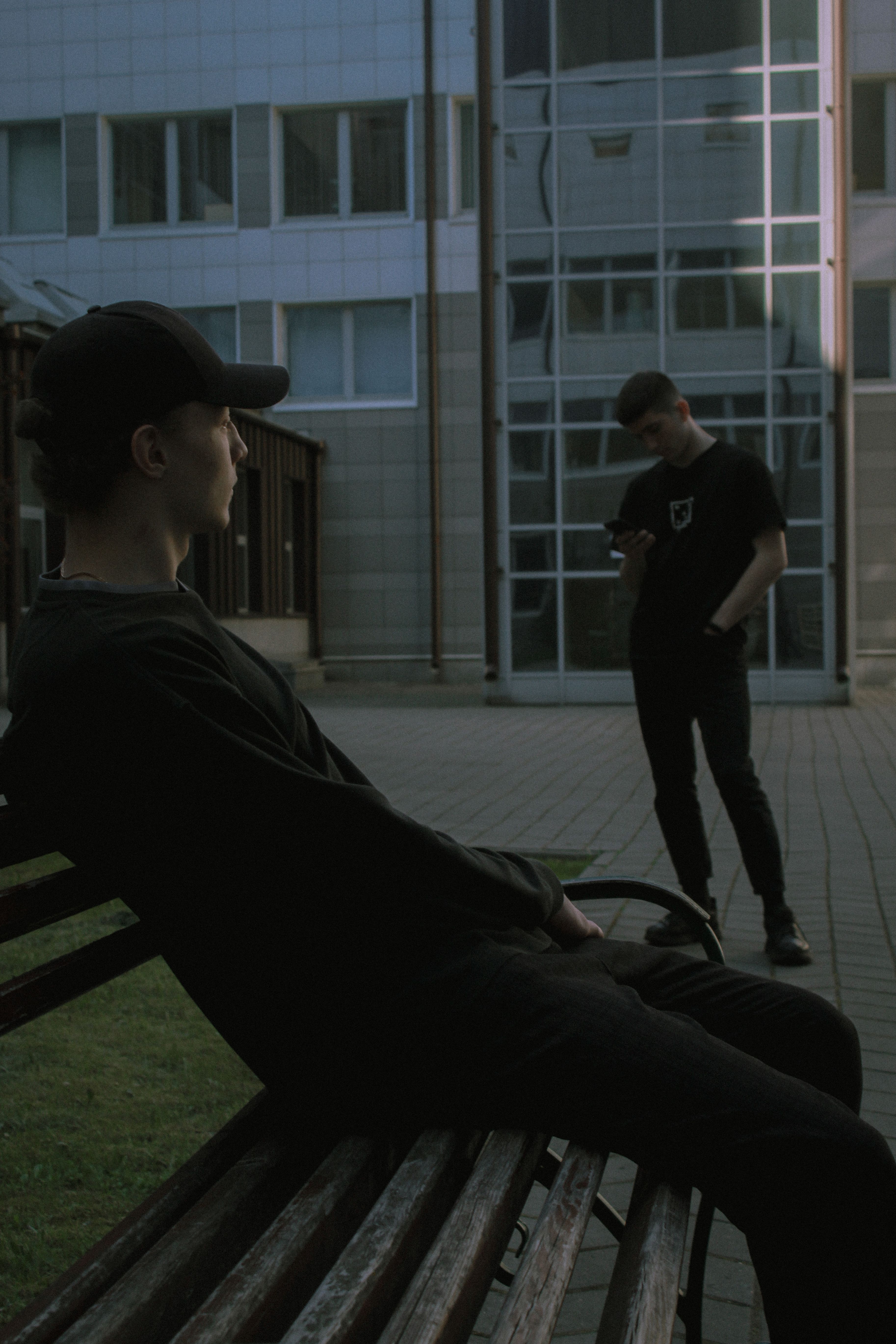 Man Sitting on Bench and Man Standing on Sidewalk · Free Stock Photo