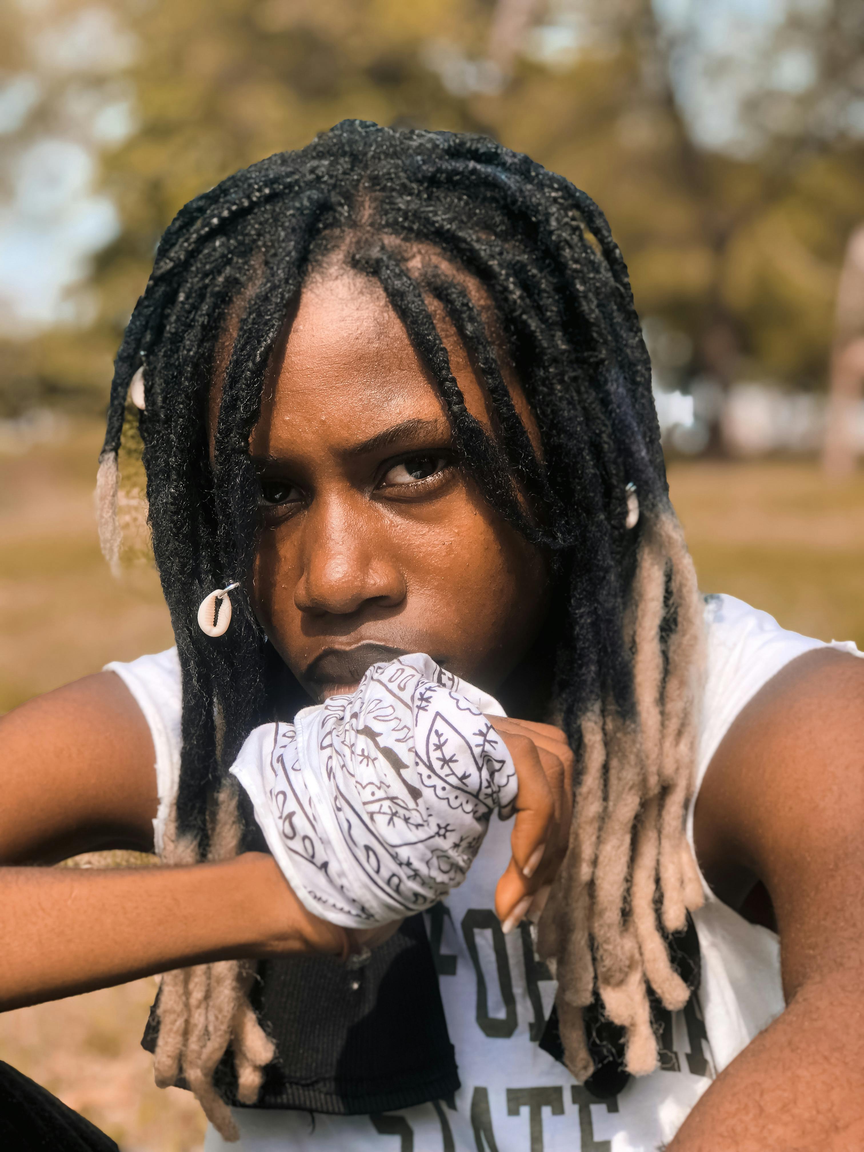 Photo of a Young Man with Dreadlocks Sitting on a Chair Between Trees ...