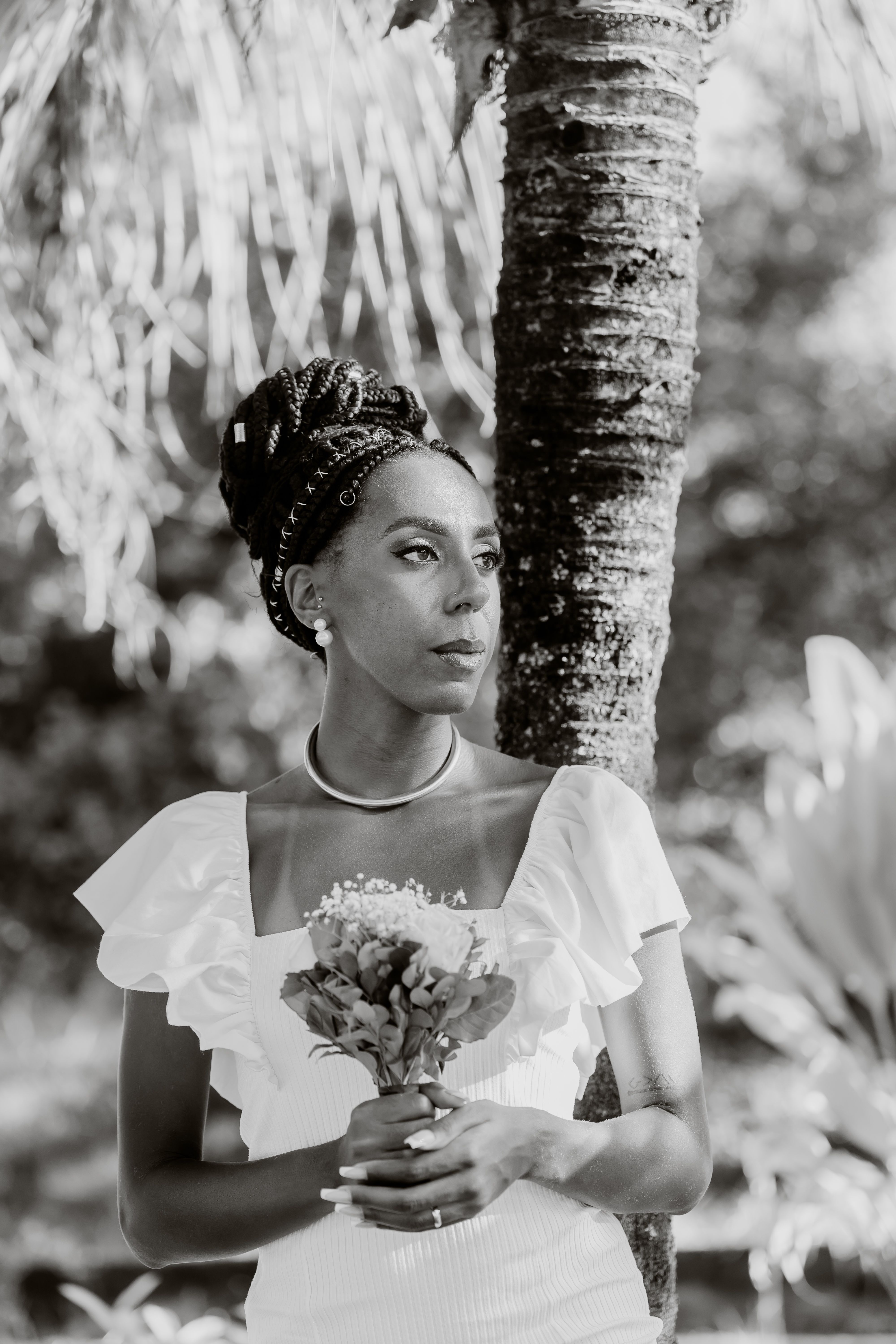 Woman with Braided hair Standing with a Bouquet under a Palm Tree ...