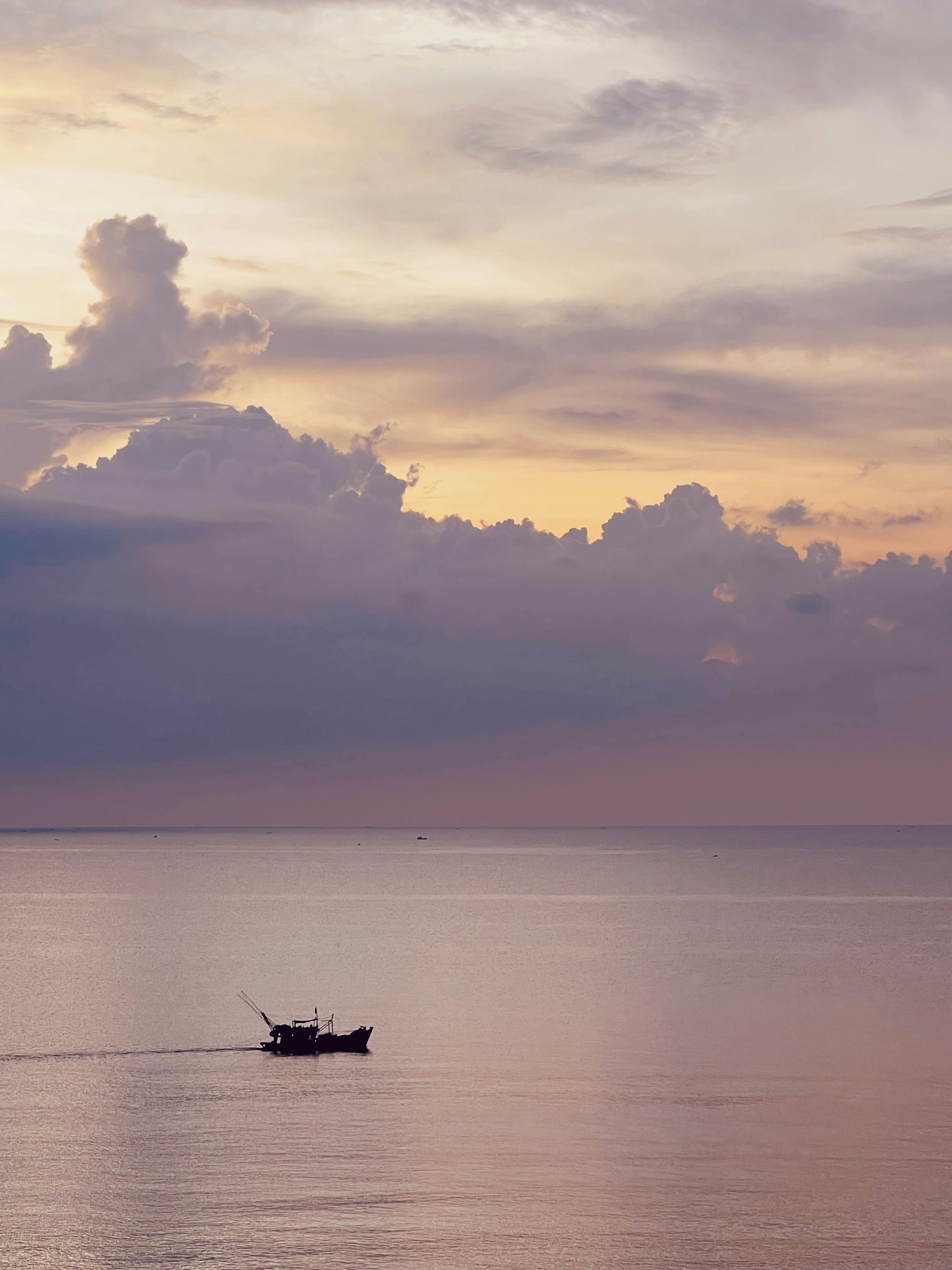 Clouds over Fishing Boat on Open Water at Sunset · Free Stock Photo