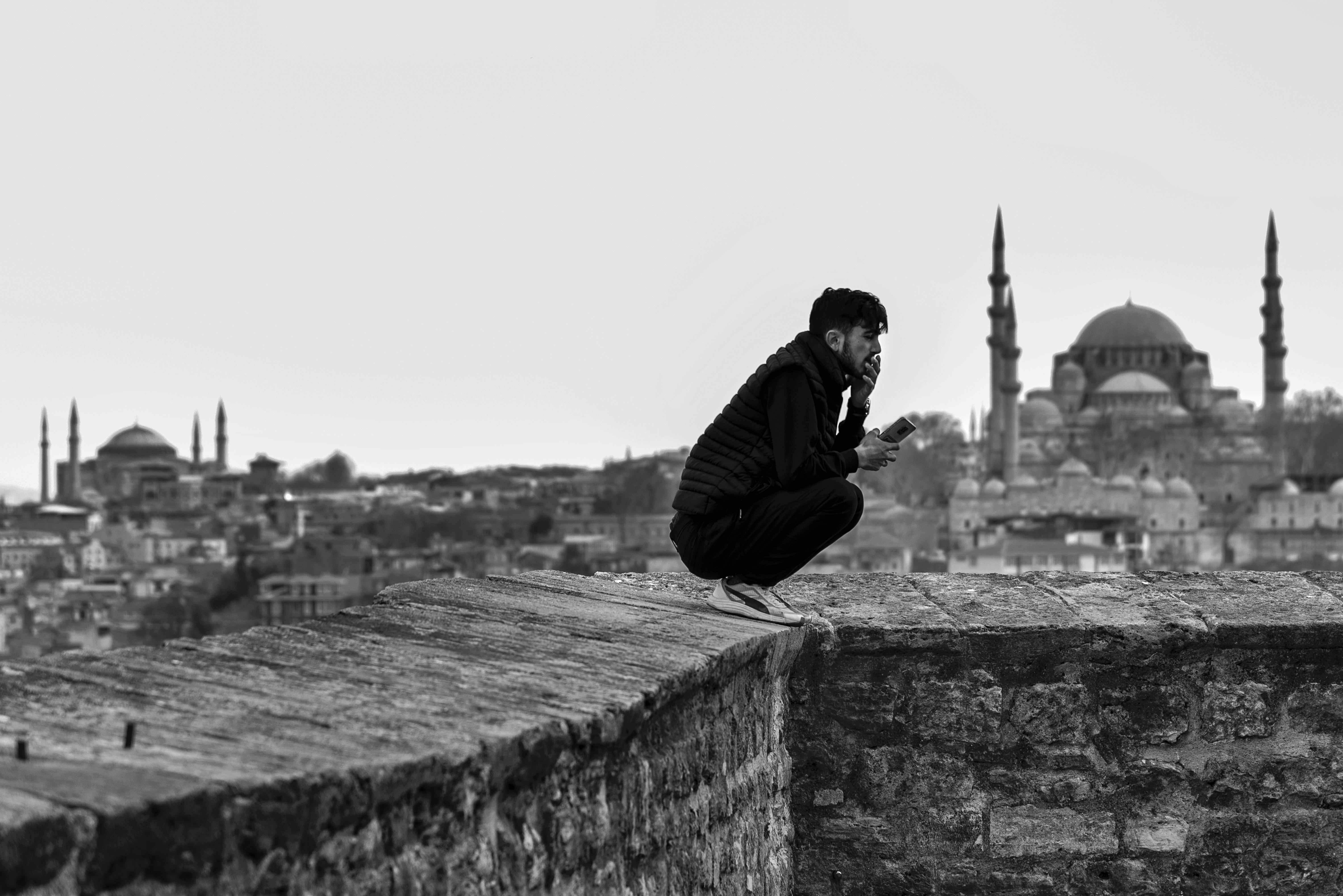 Man Crouching on Wall with Hagia Sophia behind · Free Stock Photo