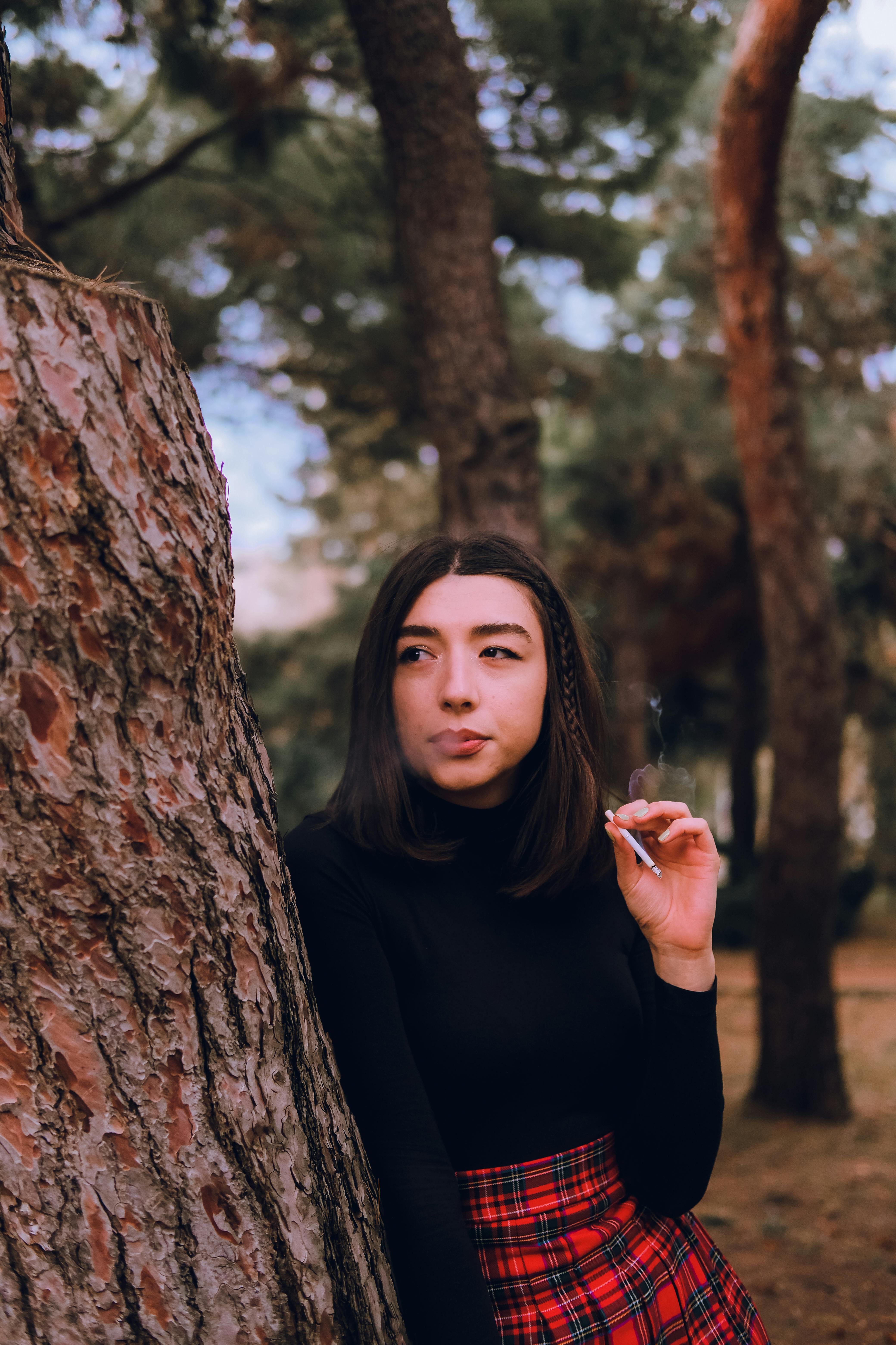 Woman Smoking Cigarette among Trees · Free Stock Photo