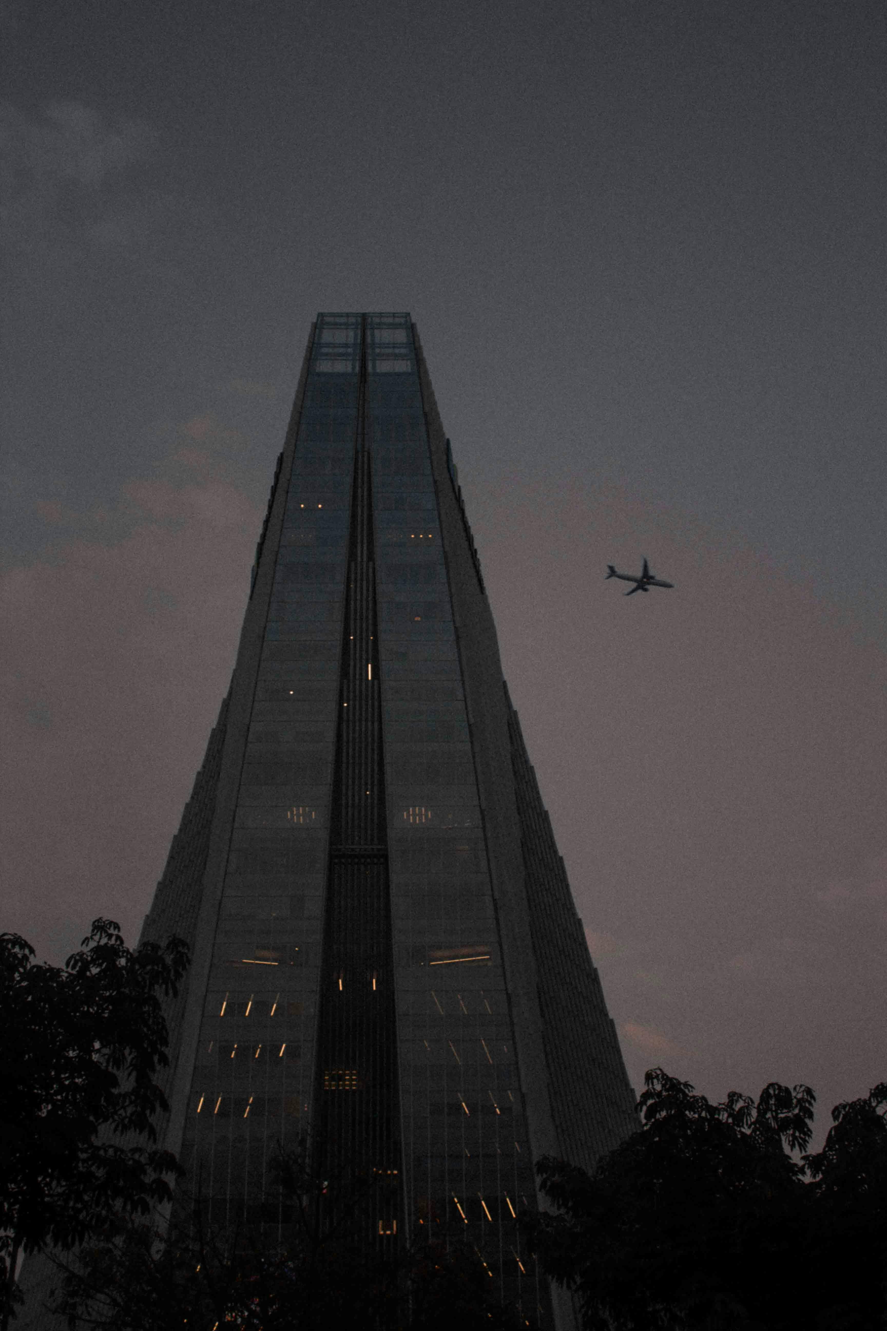 Airplane Flying near Skyscraper · Free Stock Photo