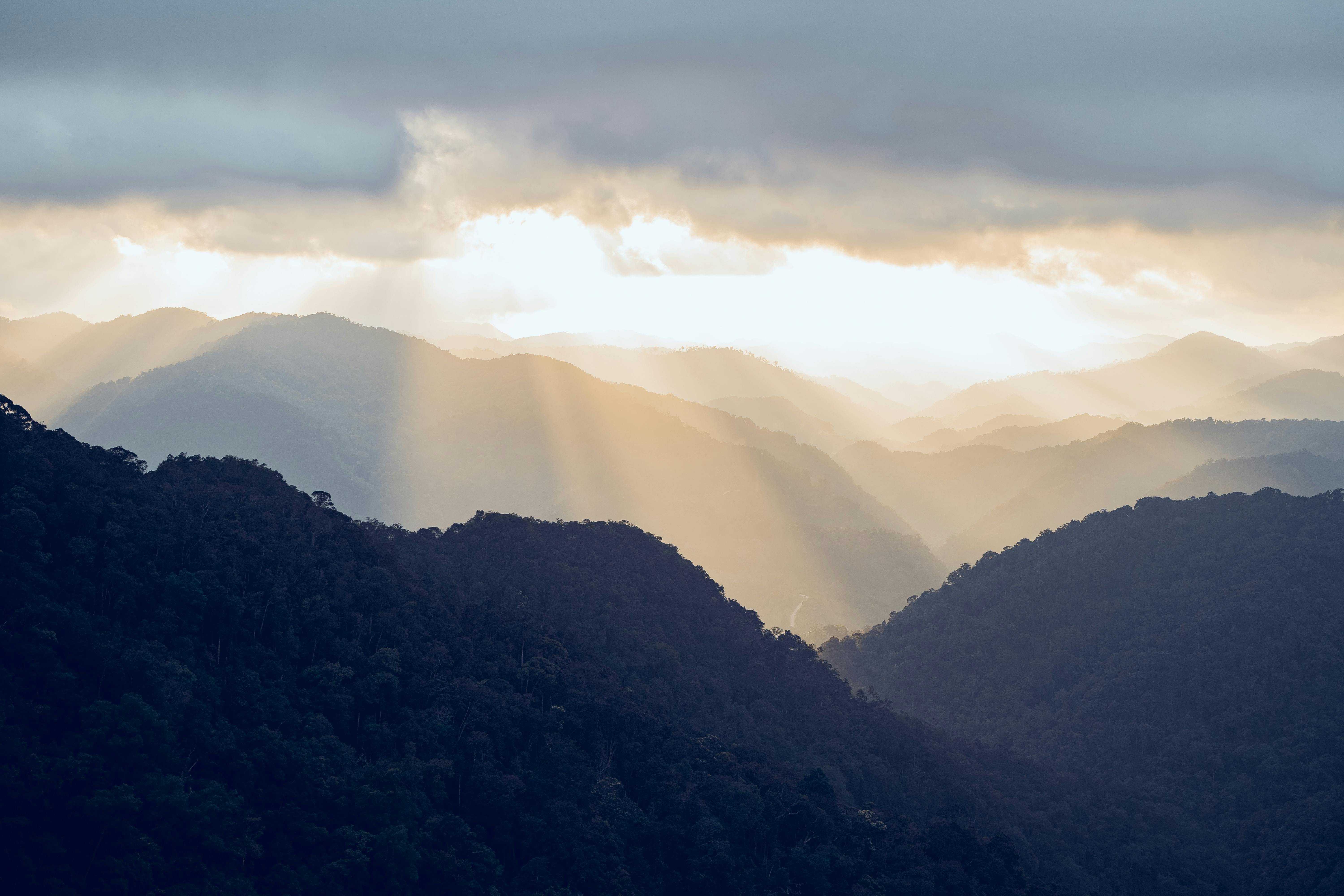 Sunlight Shining Through Clouds over Hills · Free Stock Photo