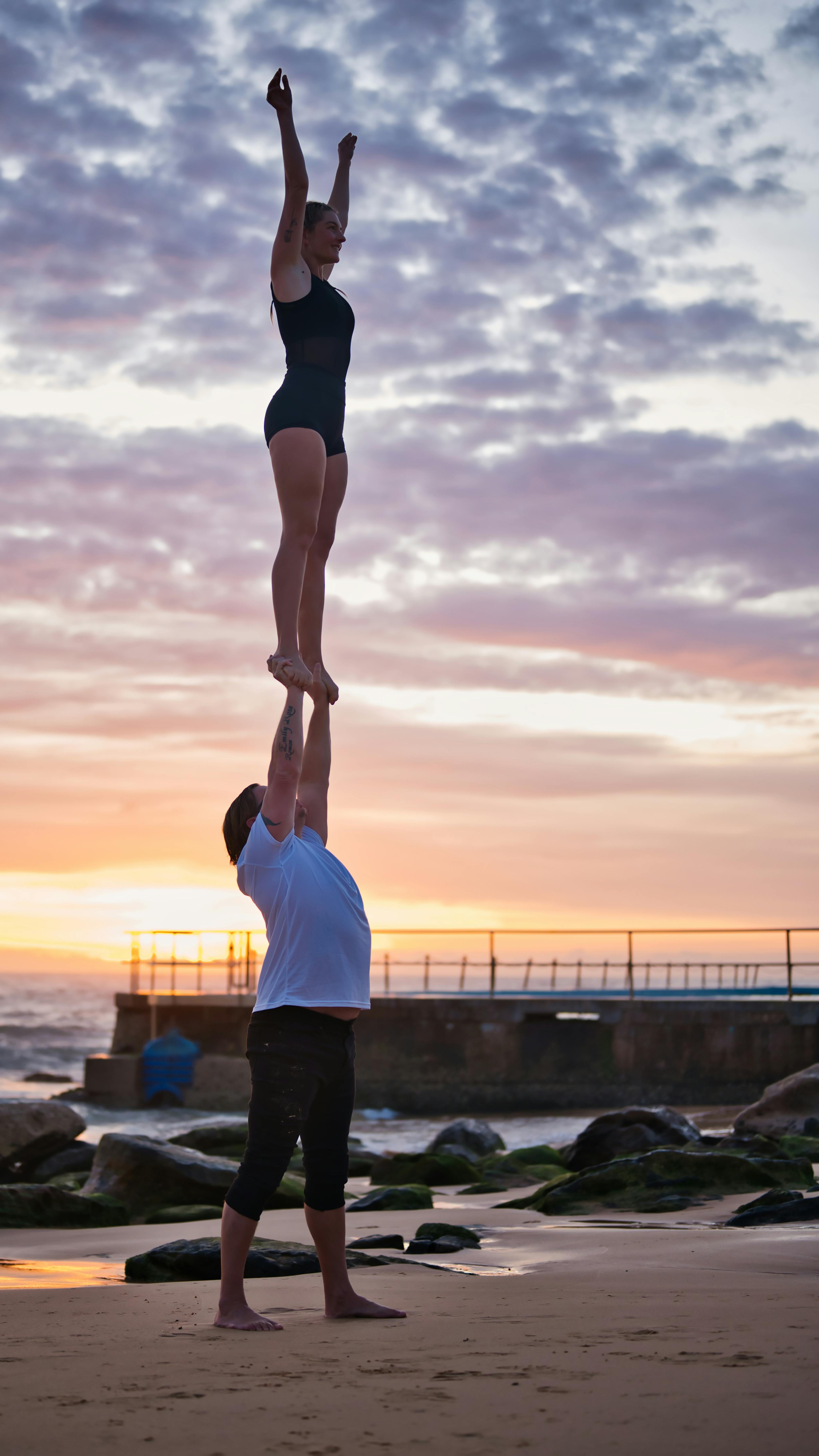 Woman Standing on Man Hands on Beach at Dusk · Free Stock Photo