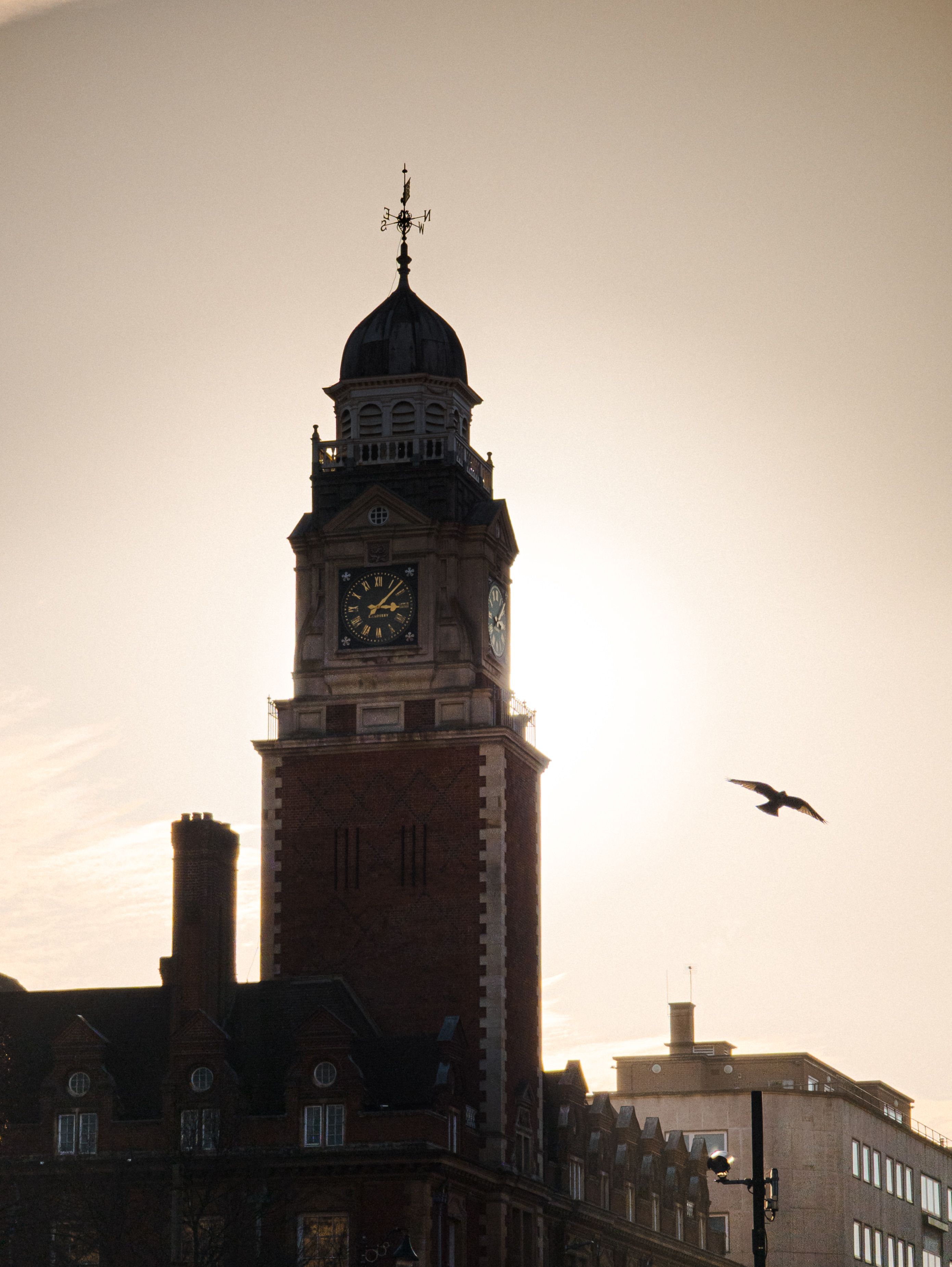 A bird flying over a clock tower in the sky · Free Stock Photo
