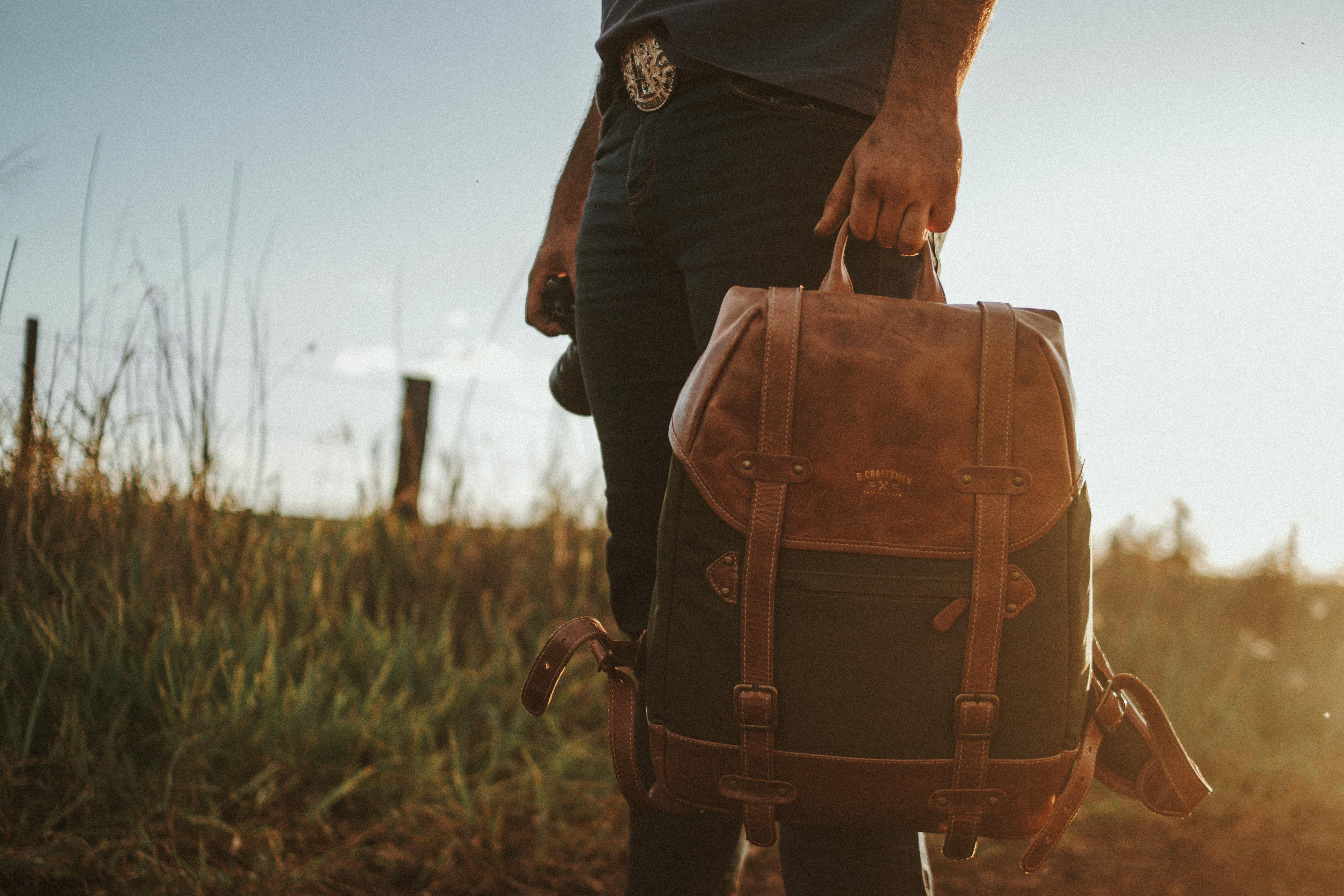 Man Holding in Hand a Vintage Backpack · Free Stock Photo