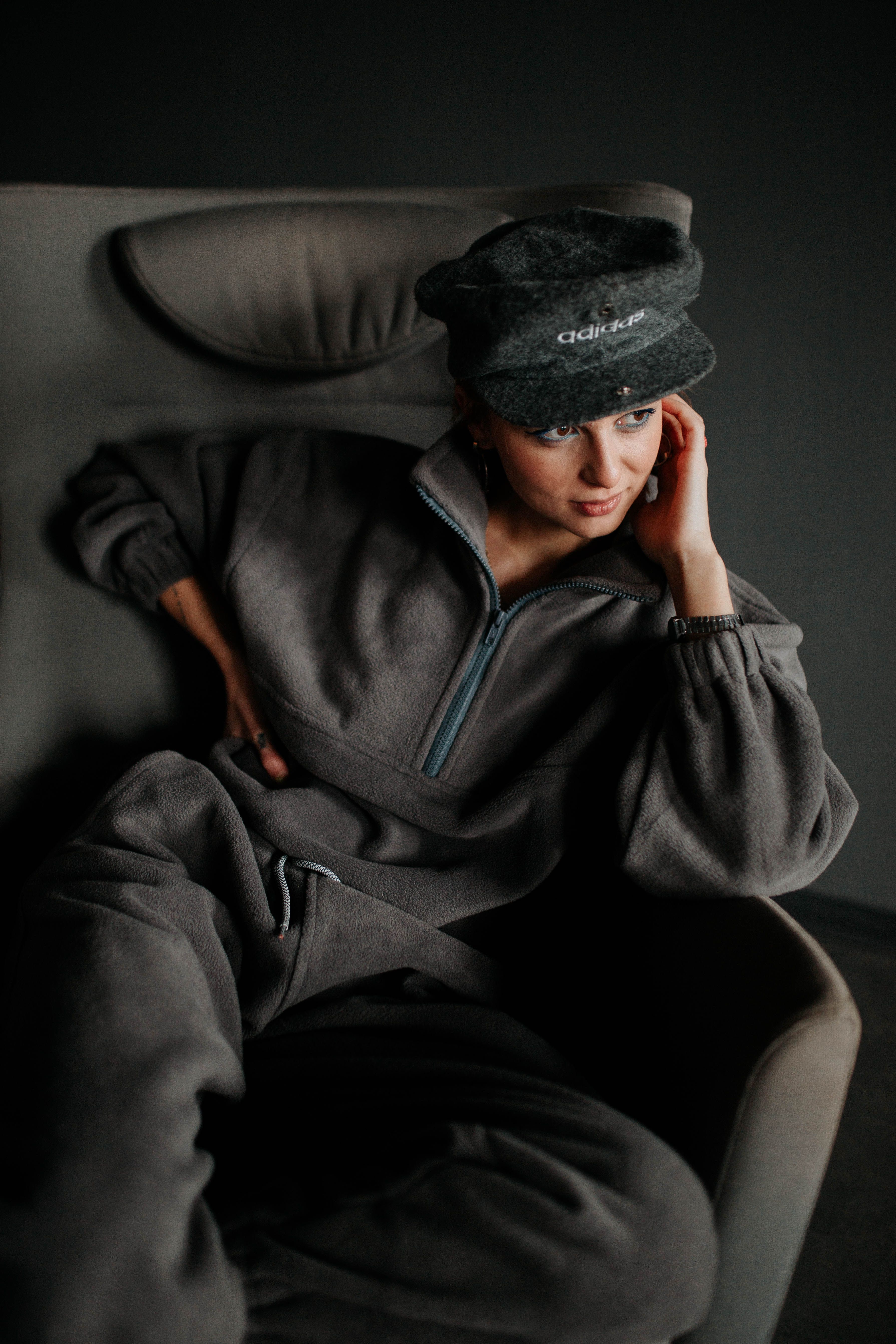 Woman Wearing a Khaki Fleece Tracksuit and a Hat Posing on an Armchair ...