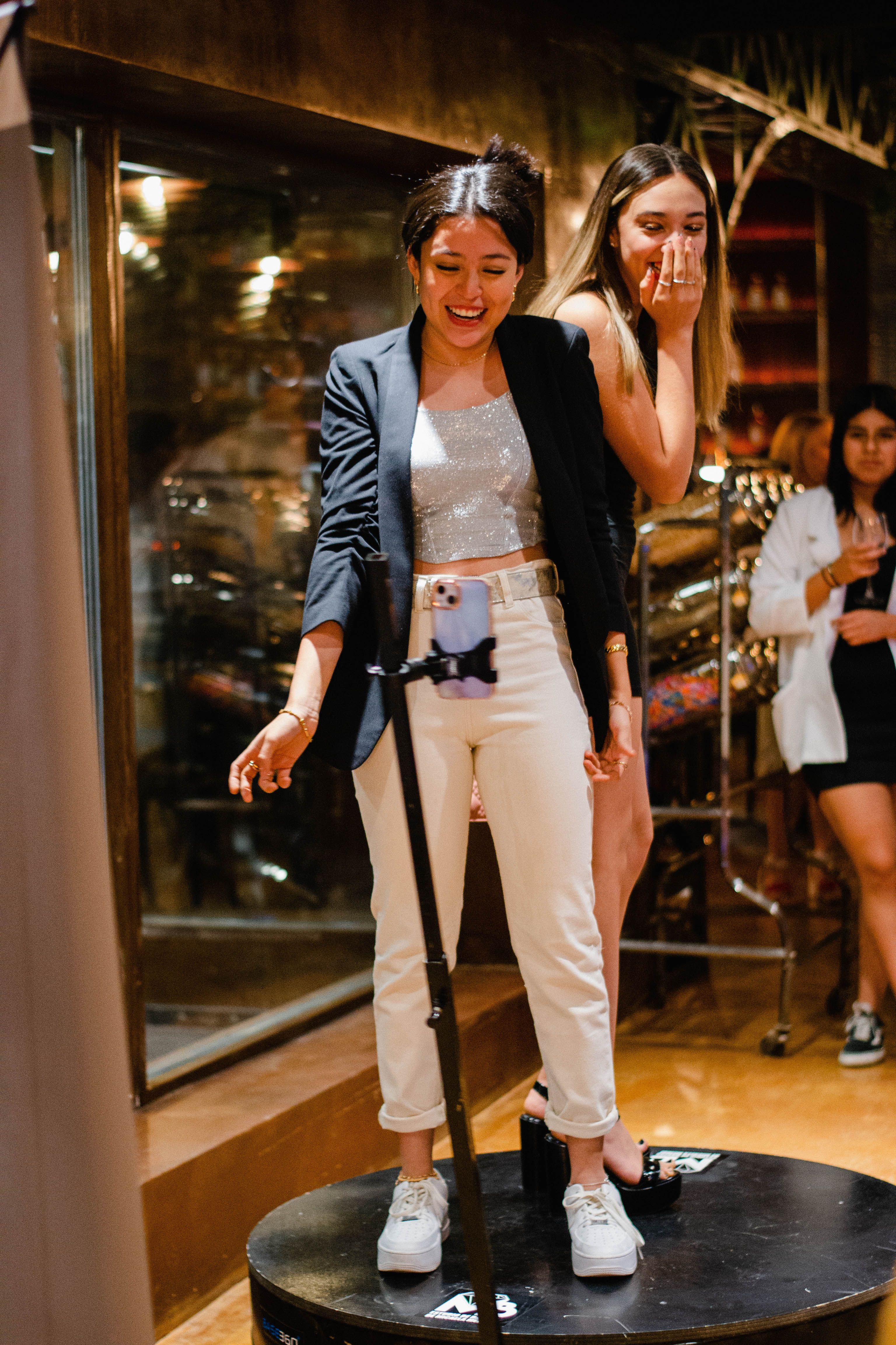Photo of Two Laughing Young Women Standing on a Pedestal at a Party ...