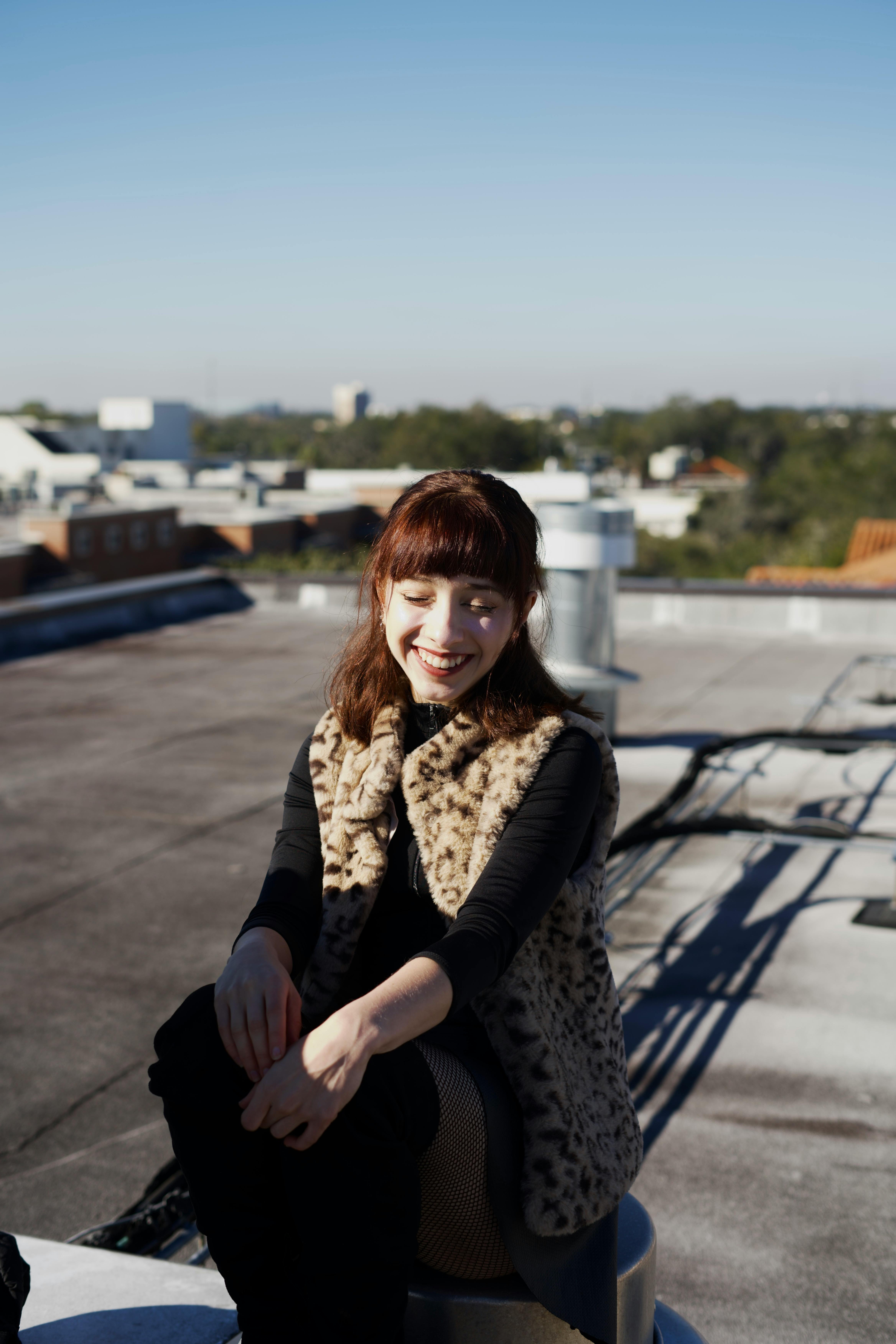 Smiling Redhead Woman Posing on Building Roof · Free Stock Photo