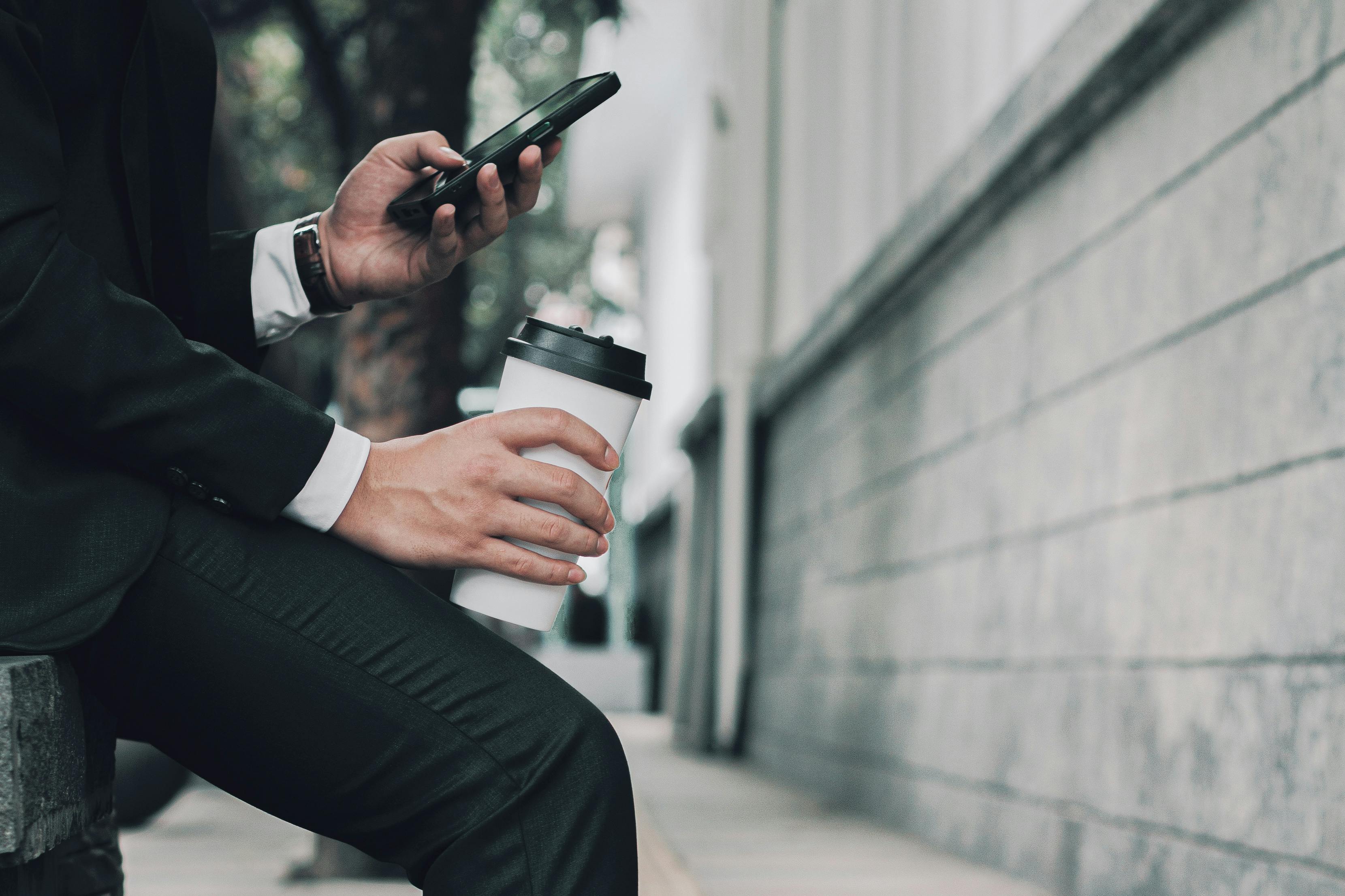 Close-up of a Man in a Suit Sitting on a Bench and Holding a Cup of ...