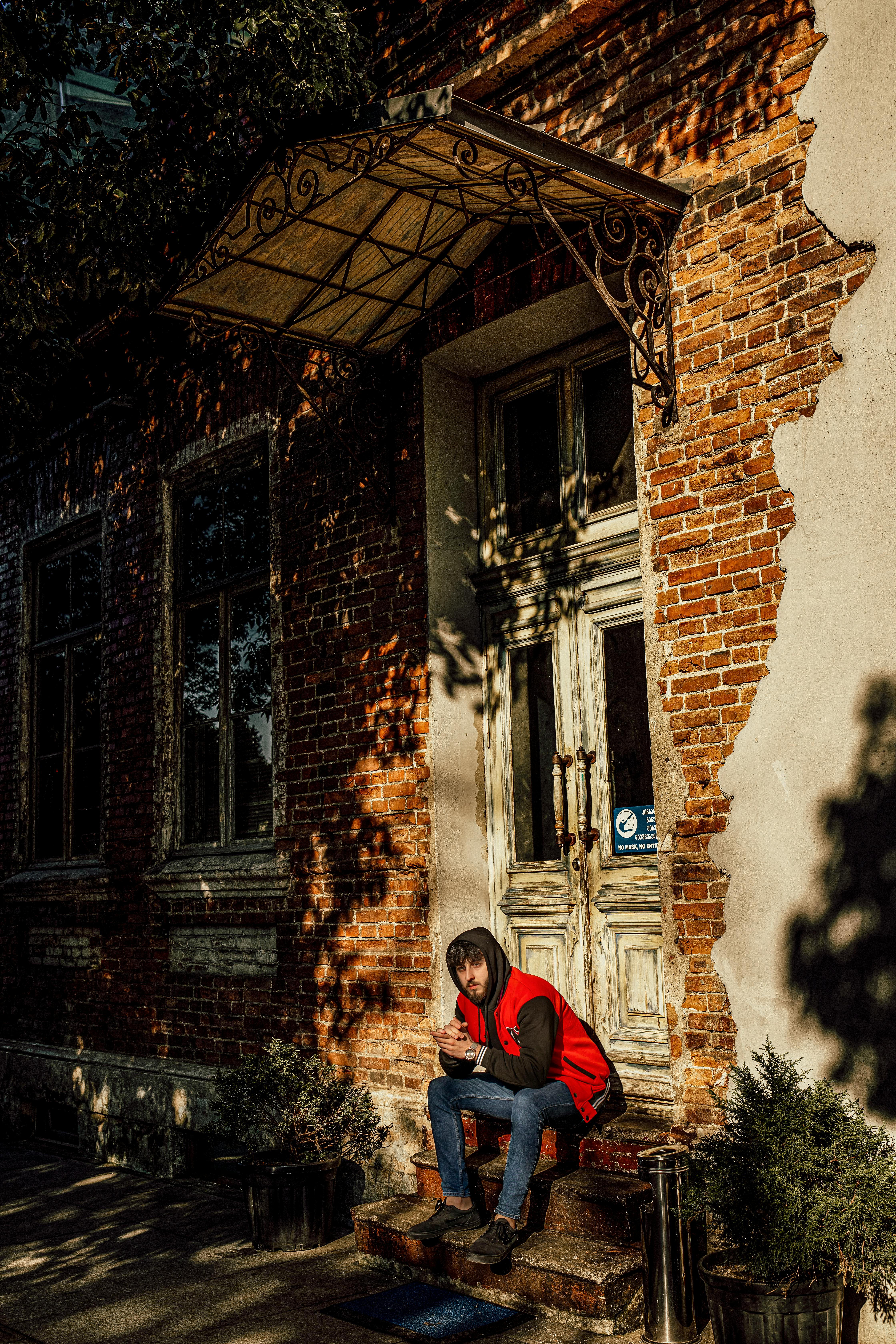 Man Sitting on a Front Stoop · Free Stock Photo
