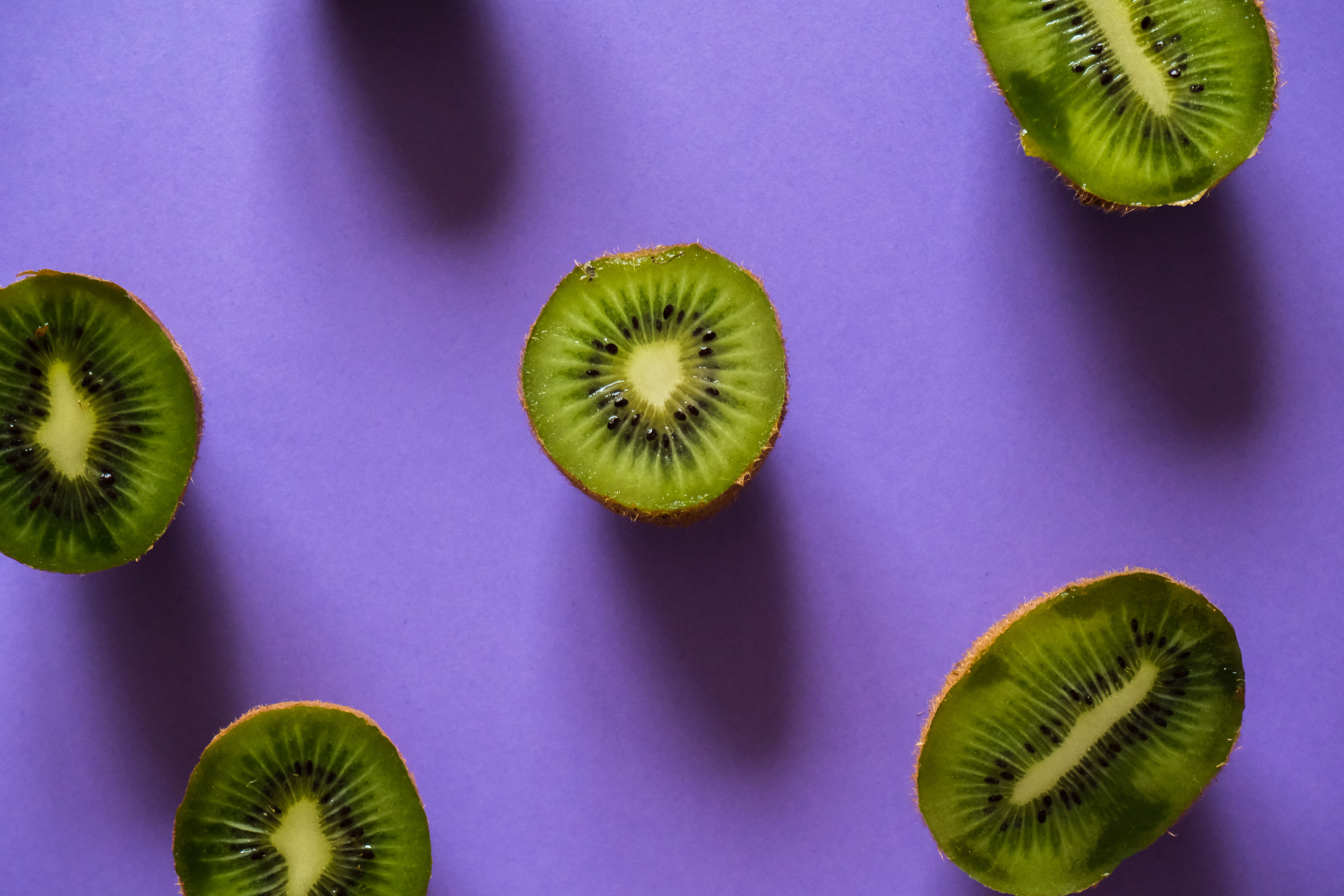 Photo of Kiwi Halves on a Purple Background · Free Stock Photo