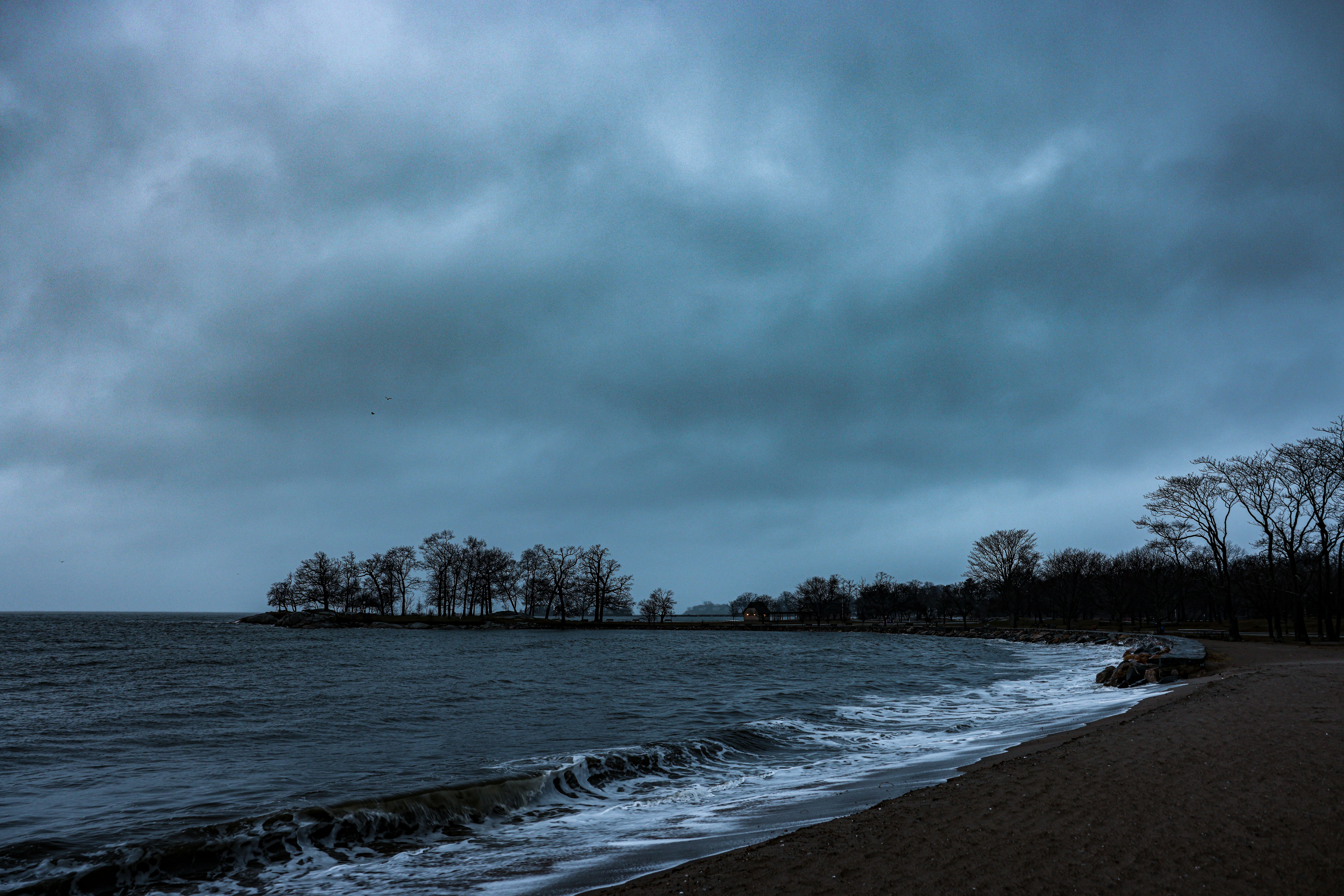 View of a Beach and Sea under a Dark, Cloudy Sky · Free Stock Photo
