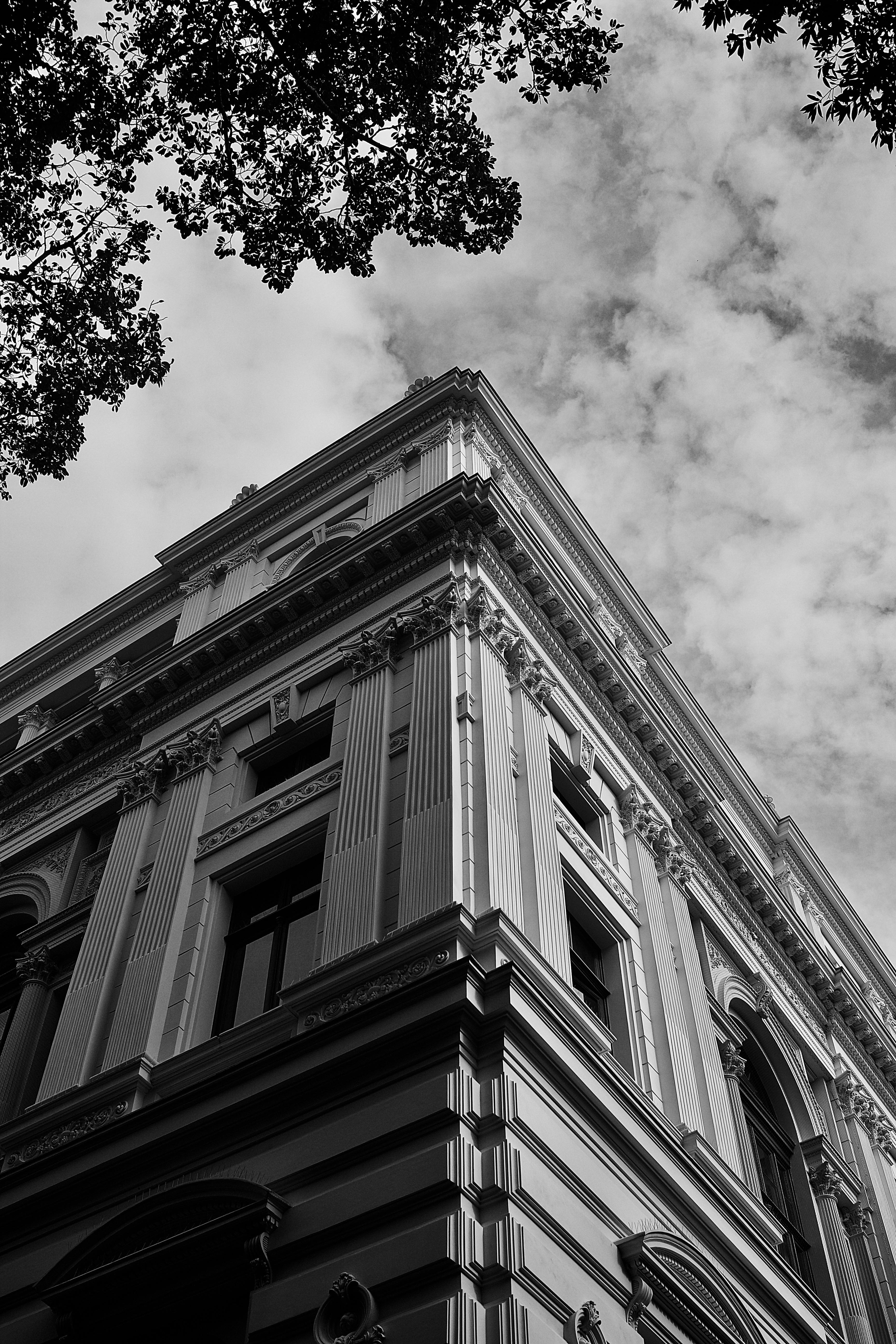 Black and white photo of a building with clouds · Free Stock Photo