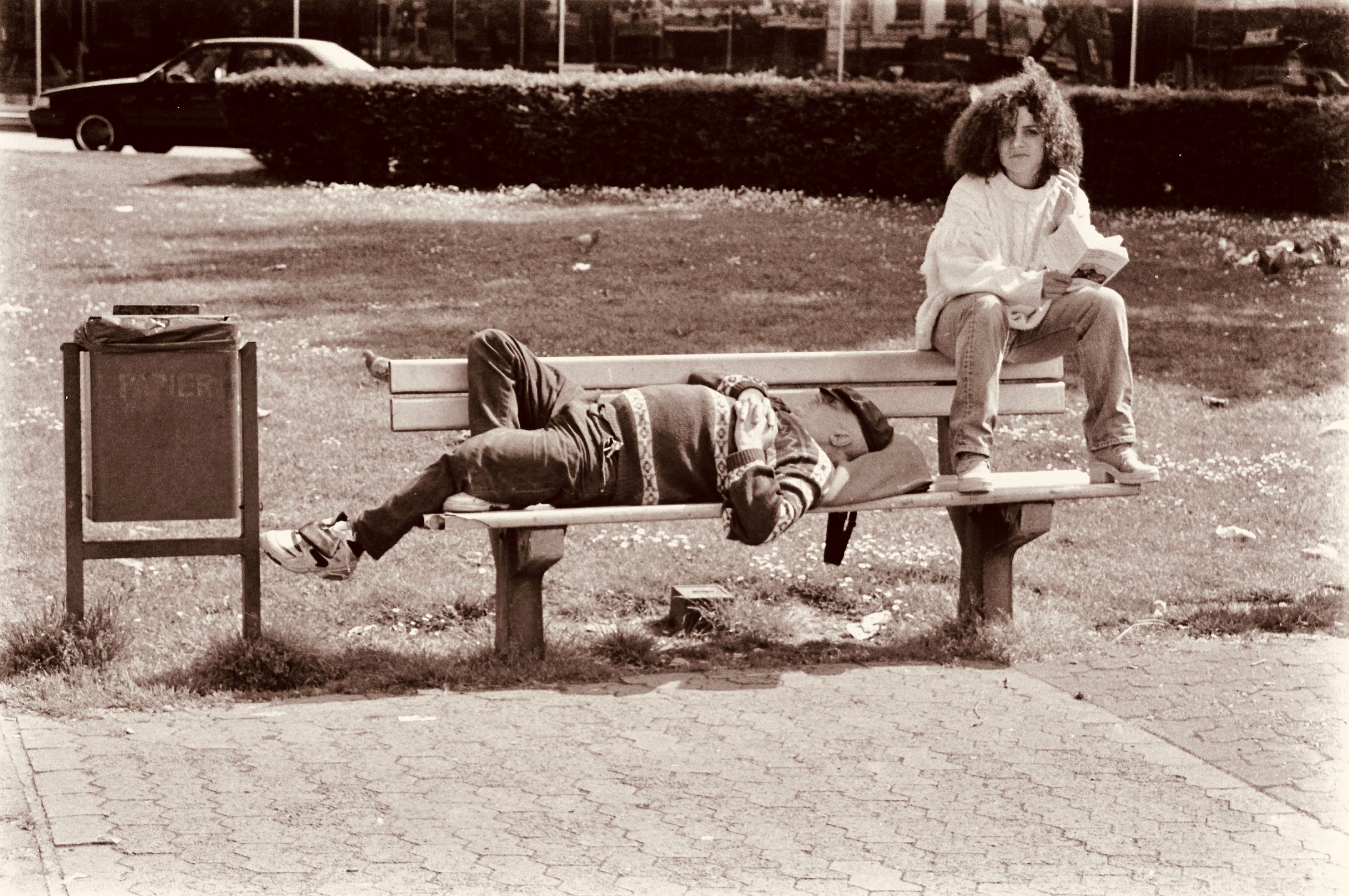 Woman Sitting on Bench and Man Lying Down · Free Stock Photo