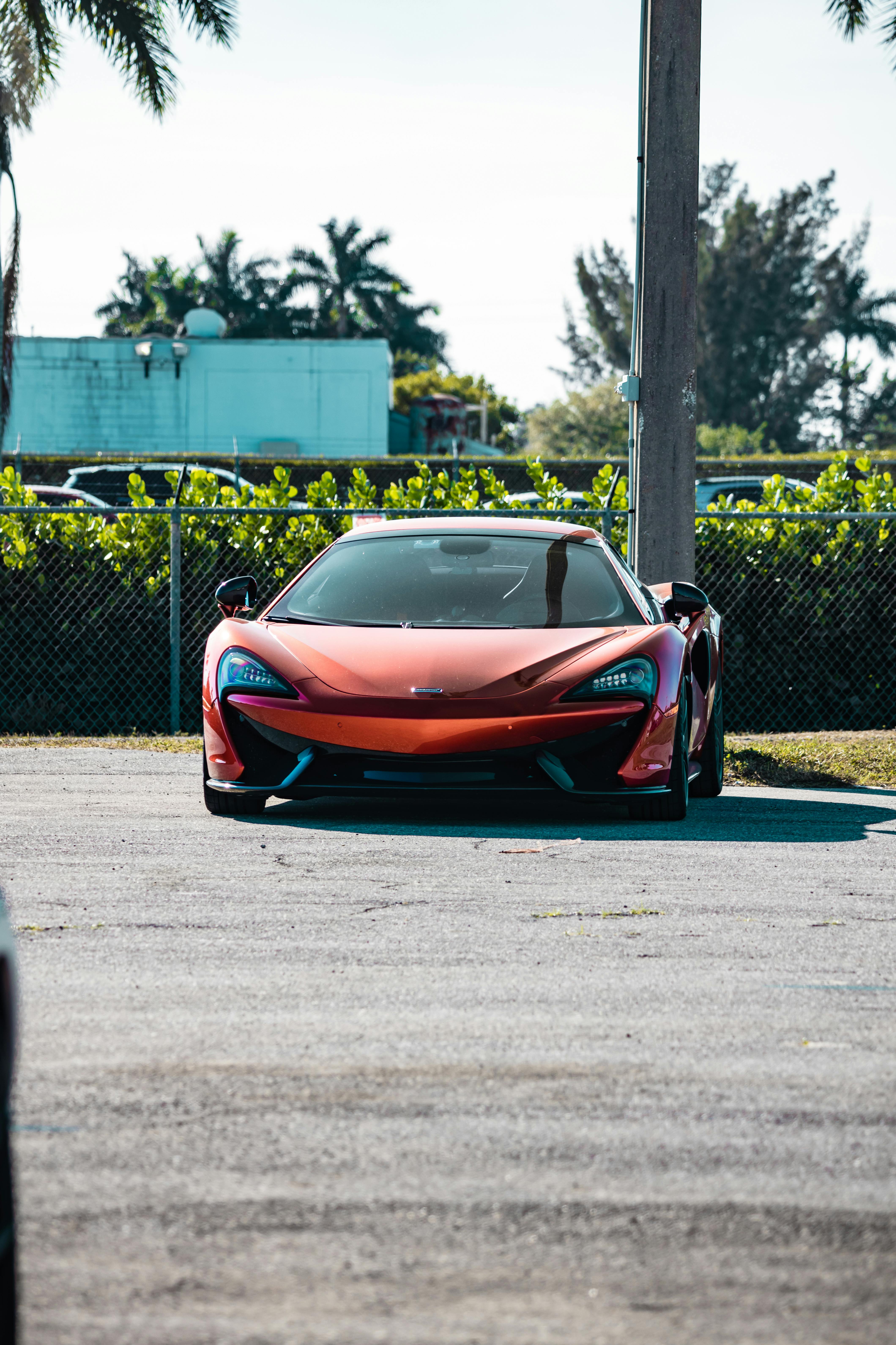 A red mclaren sports car parked in a parking lot · Free Stock Photo