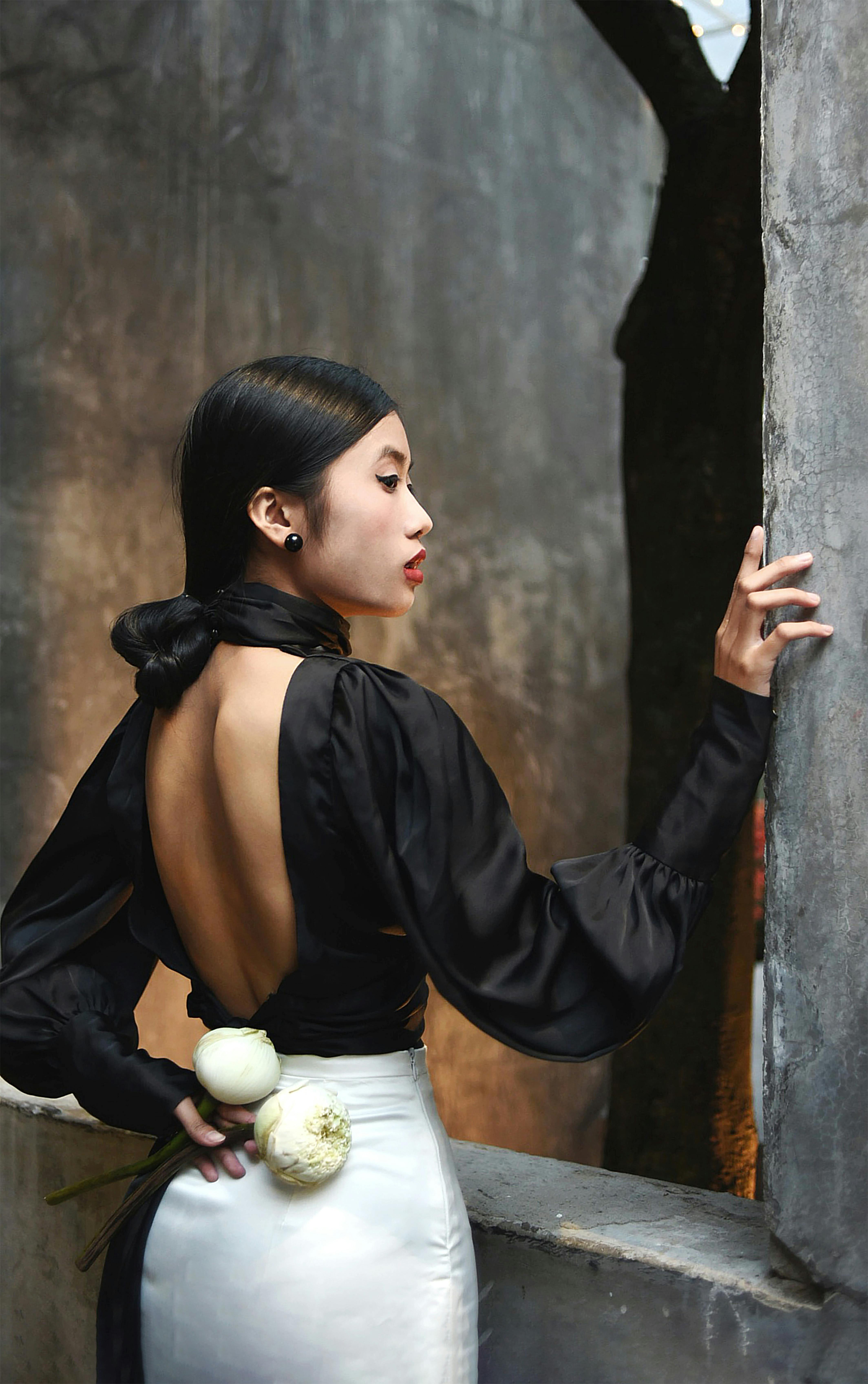Woman Posing in a Black Blouse with Back Decollete by a Concrete Wall ...