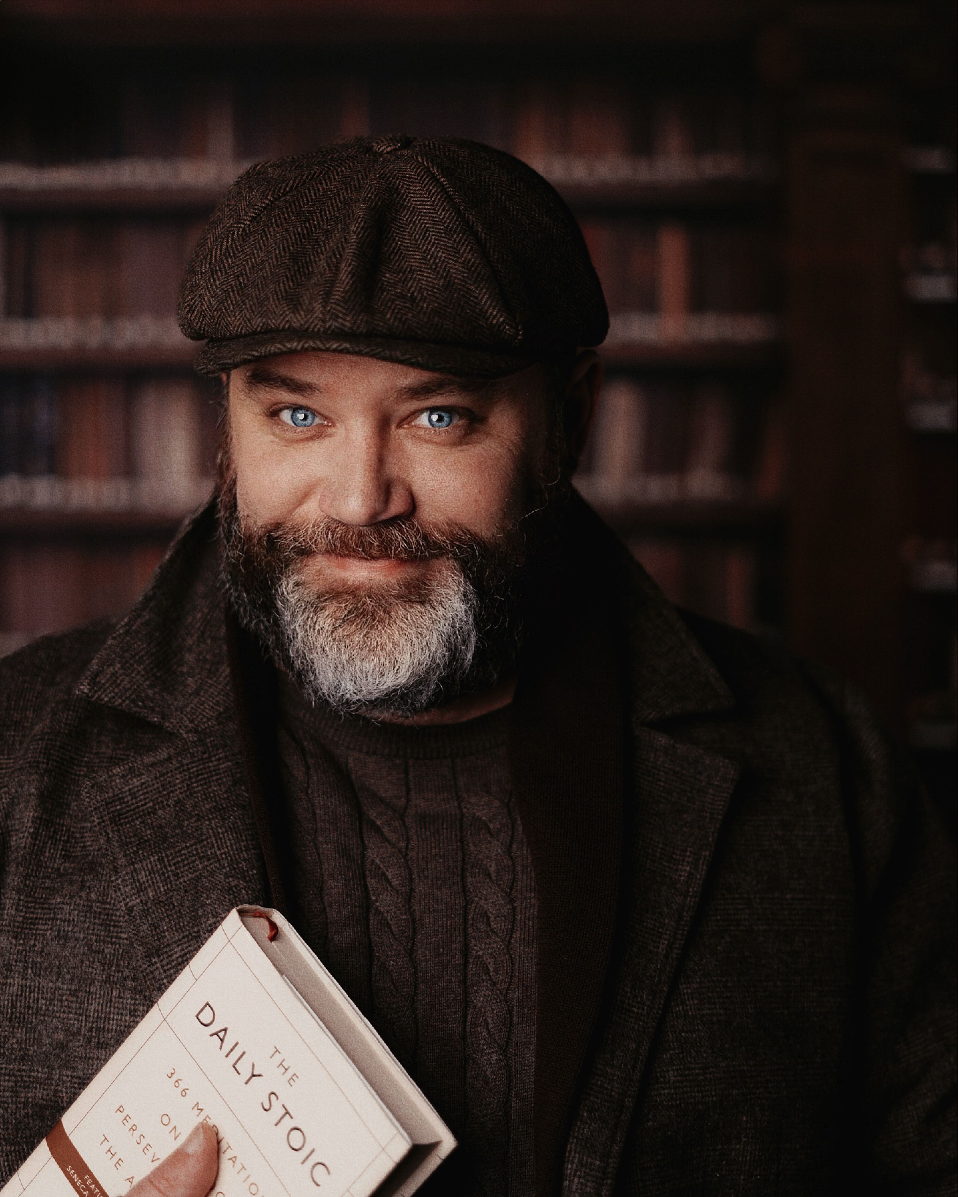 Portrait of a Smiling Bearded Man Holding a Book · Free Stock Photo