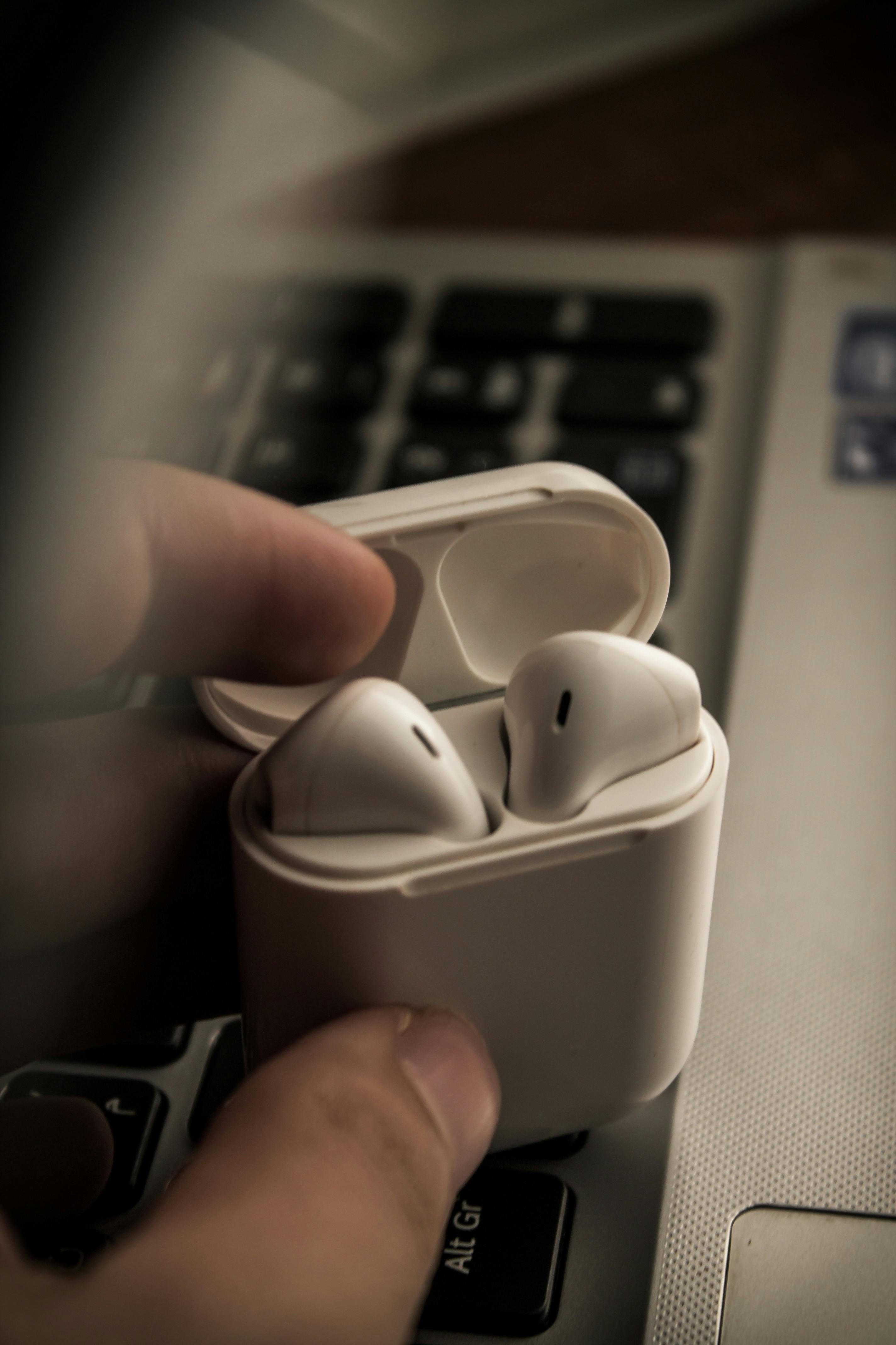 A person holding a pair of airpods in their hand · Free Stock Photo