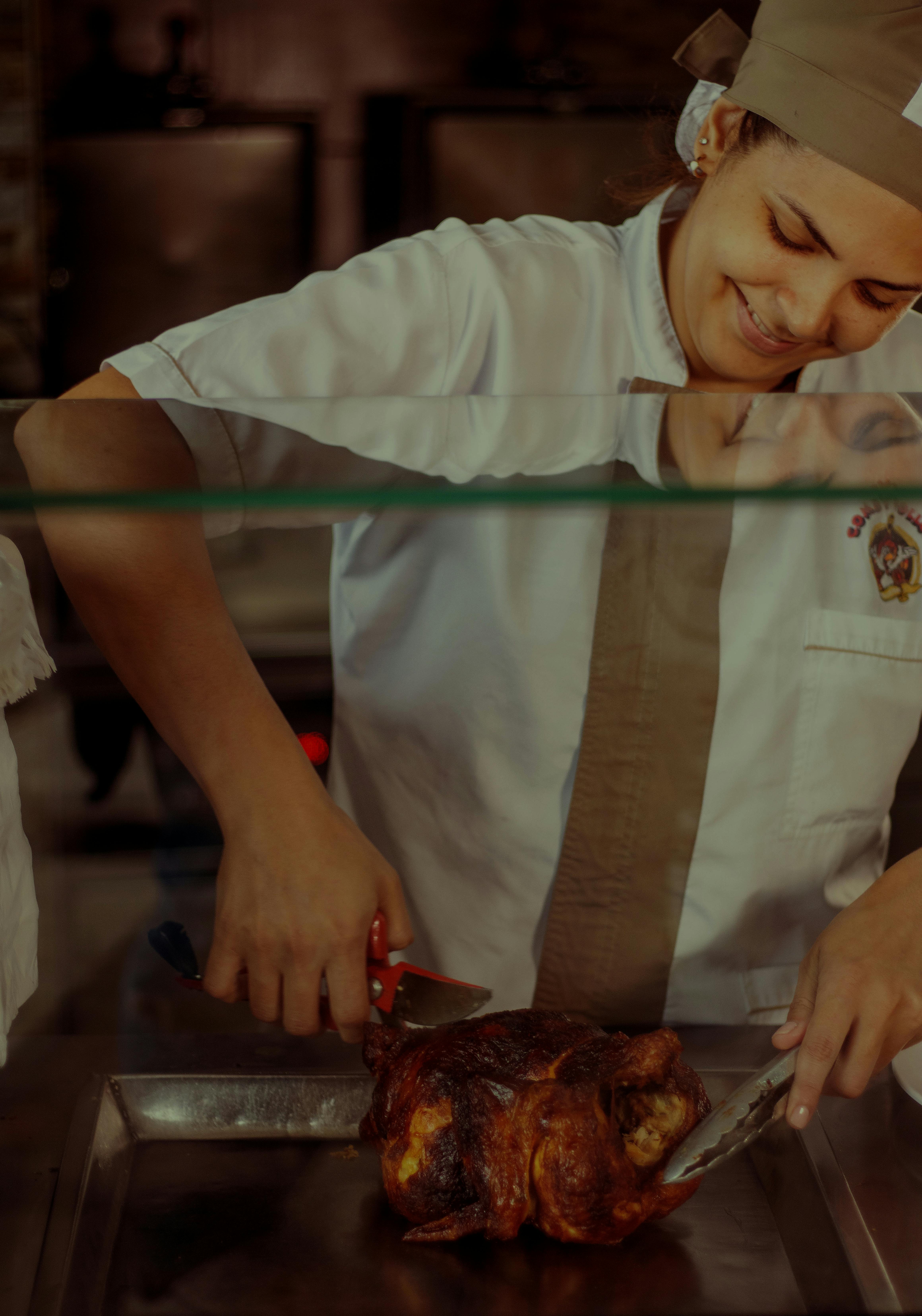 Smiling Cook Cutting Roasted Chicken · Free Stock Photo