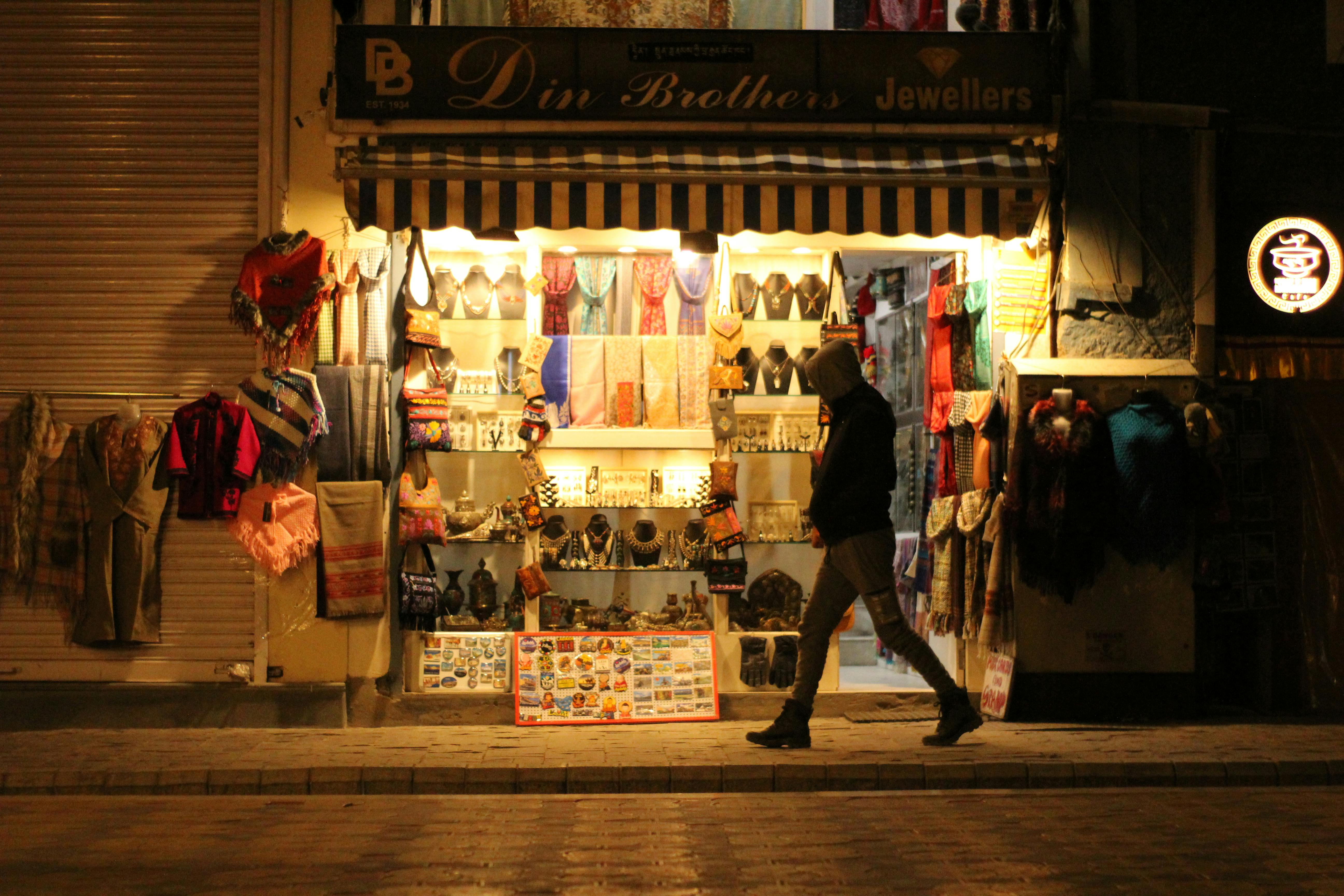 Hooded Person Walking Past an Illuminated Jewelry Store at Night · Free ...