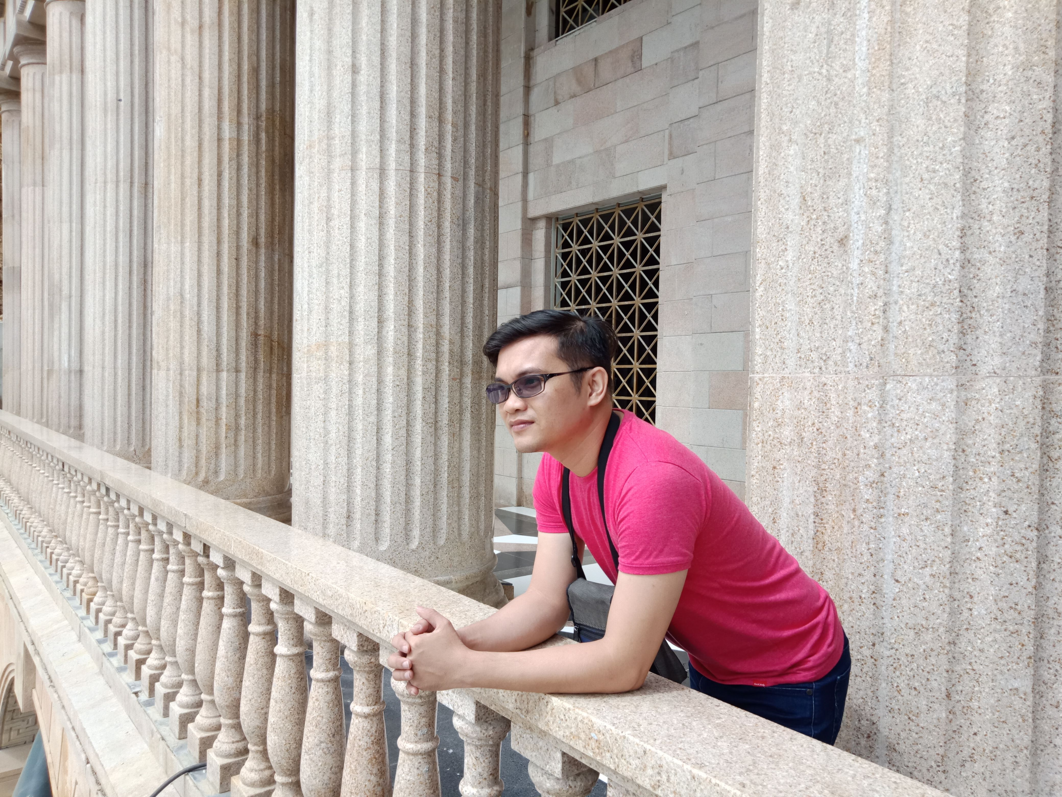 Man in T-shirt Standing and Leaning on Railing near Columns · Free ...