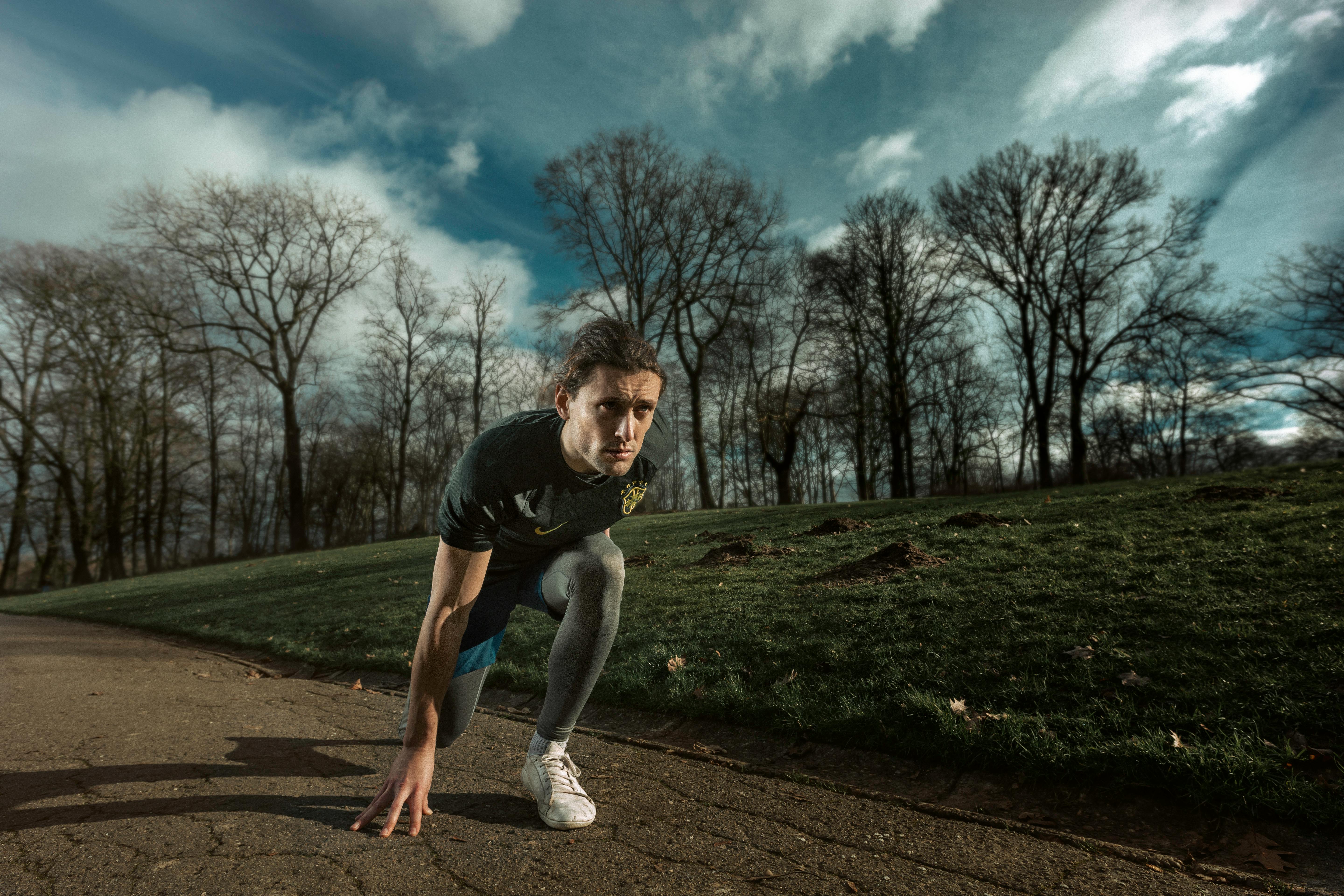 Sprinter Crouching on Asphalt at Park · Free Stock Photo