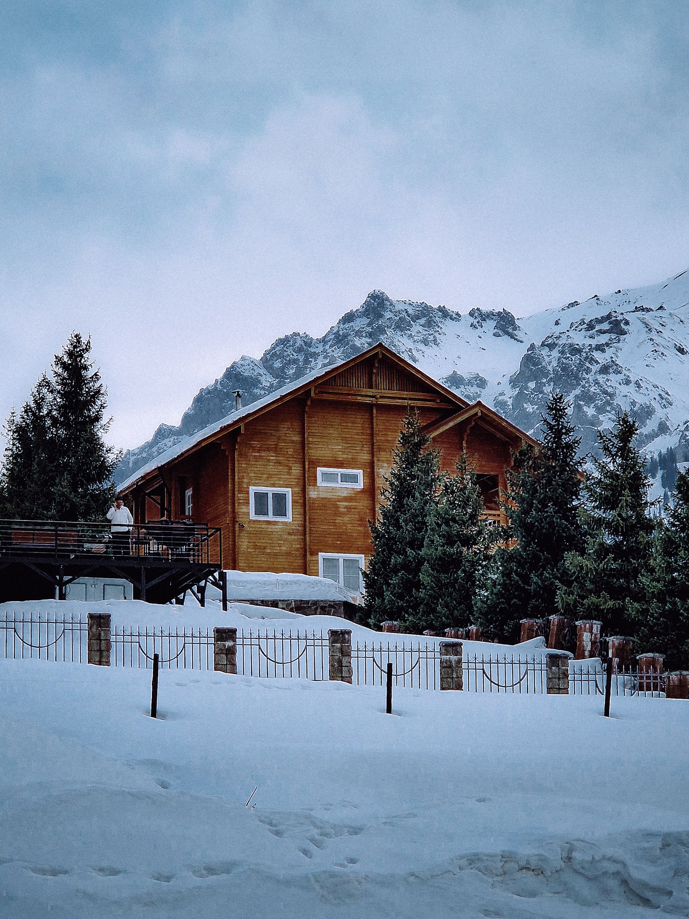 A wooden house in the snow with mountains in the background · Free ...
