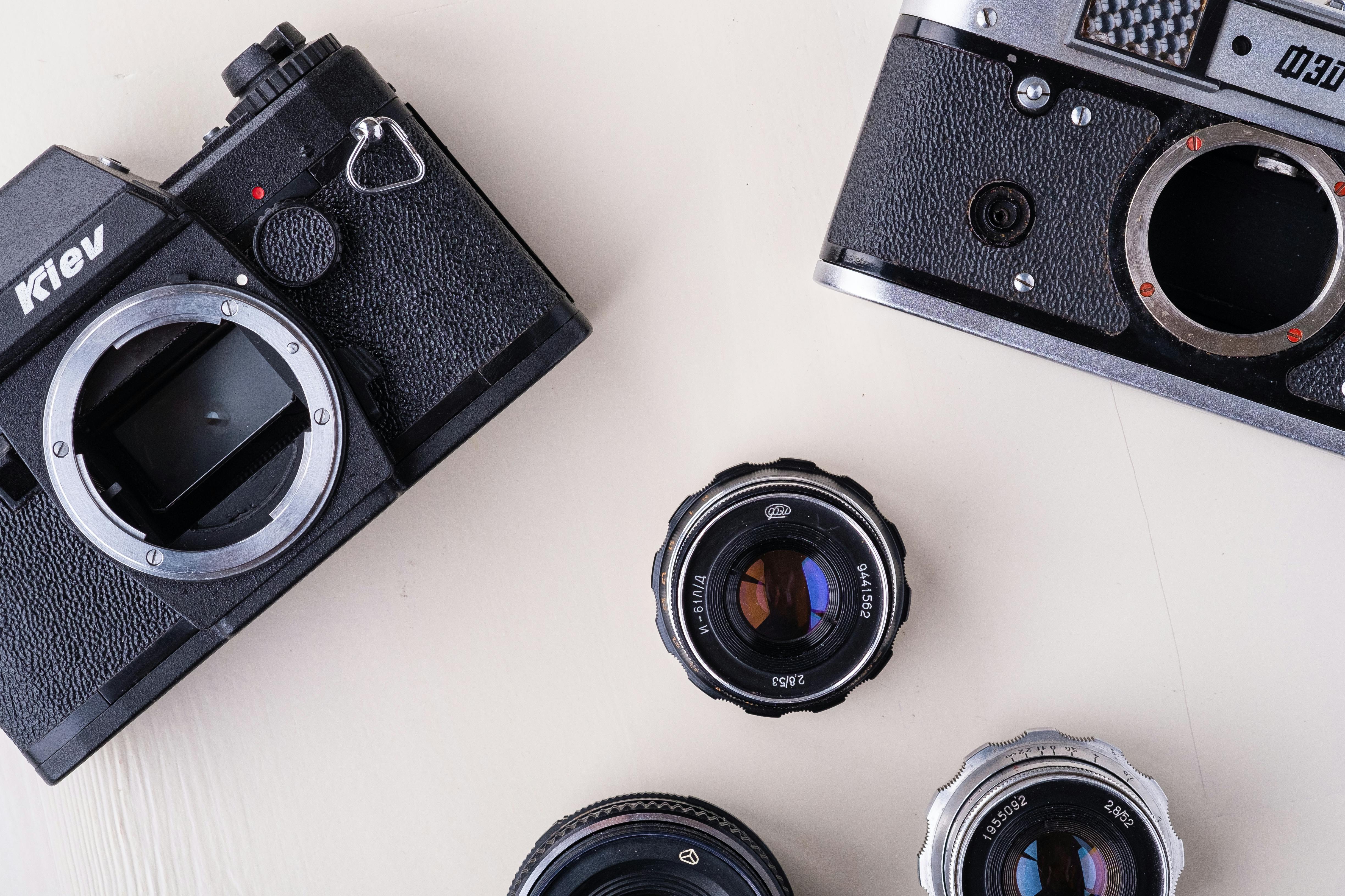 A group of cameras and lenses on a white surface · Free Stock Photo