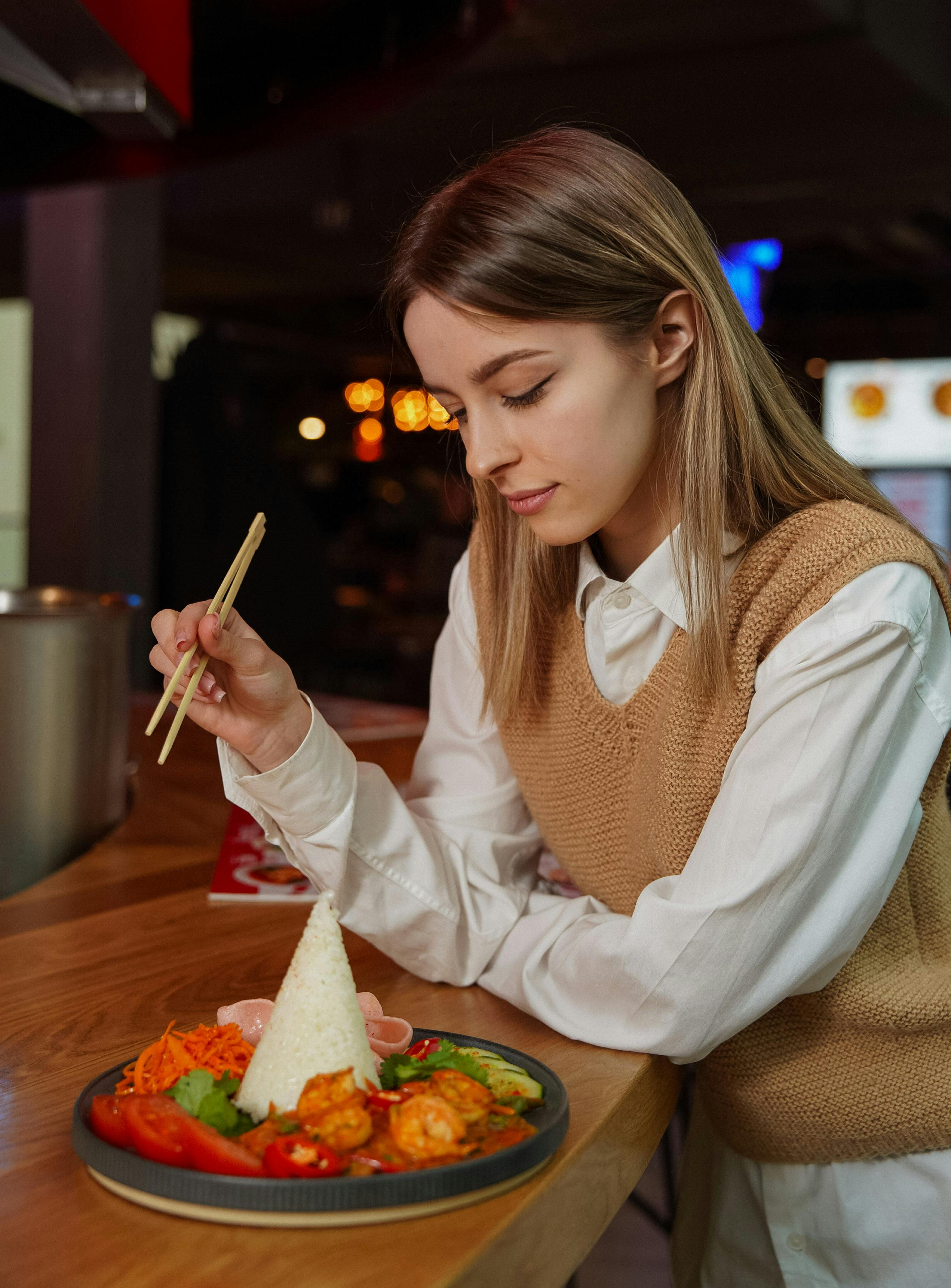Blond Girl Eating a Vegetable Dish in a Bar Using Chopsticks · Free ...