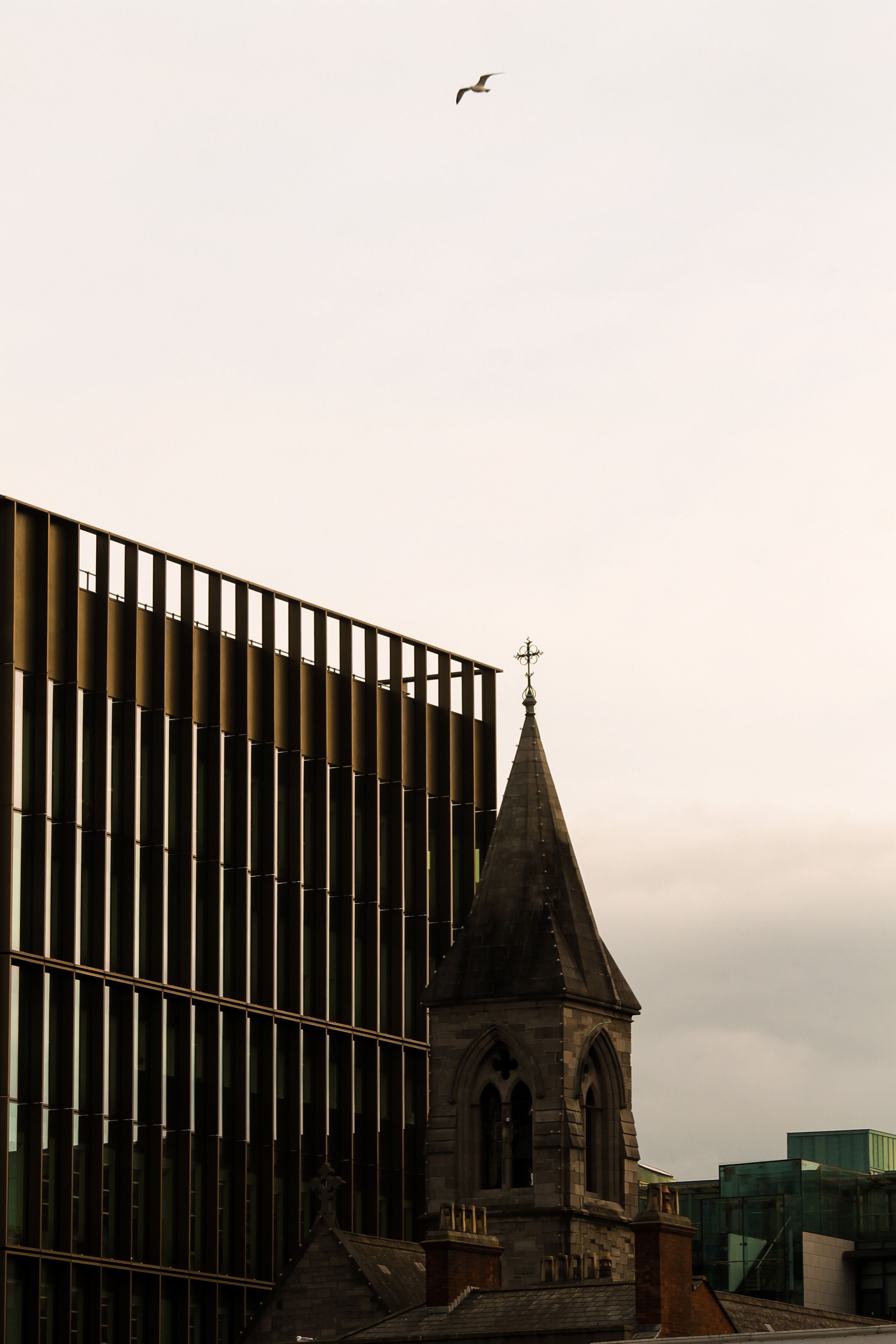 A Church Tower and a Modern Building Facade in City · Free Stock Photo