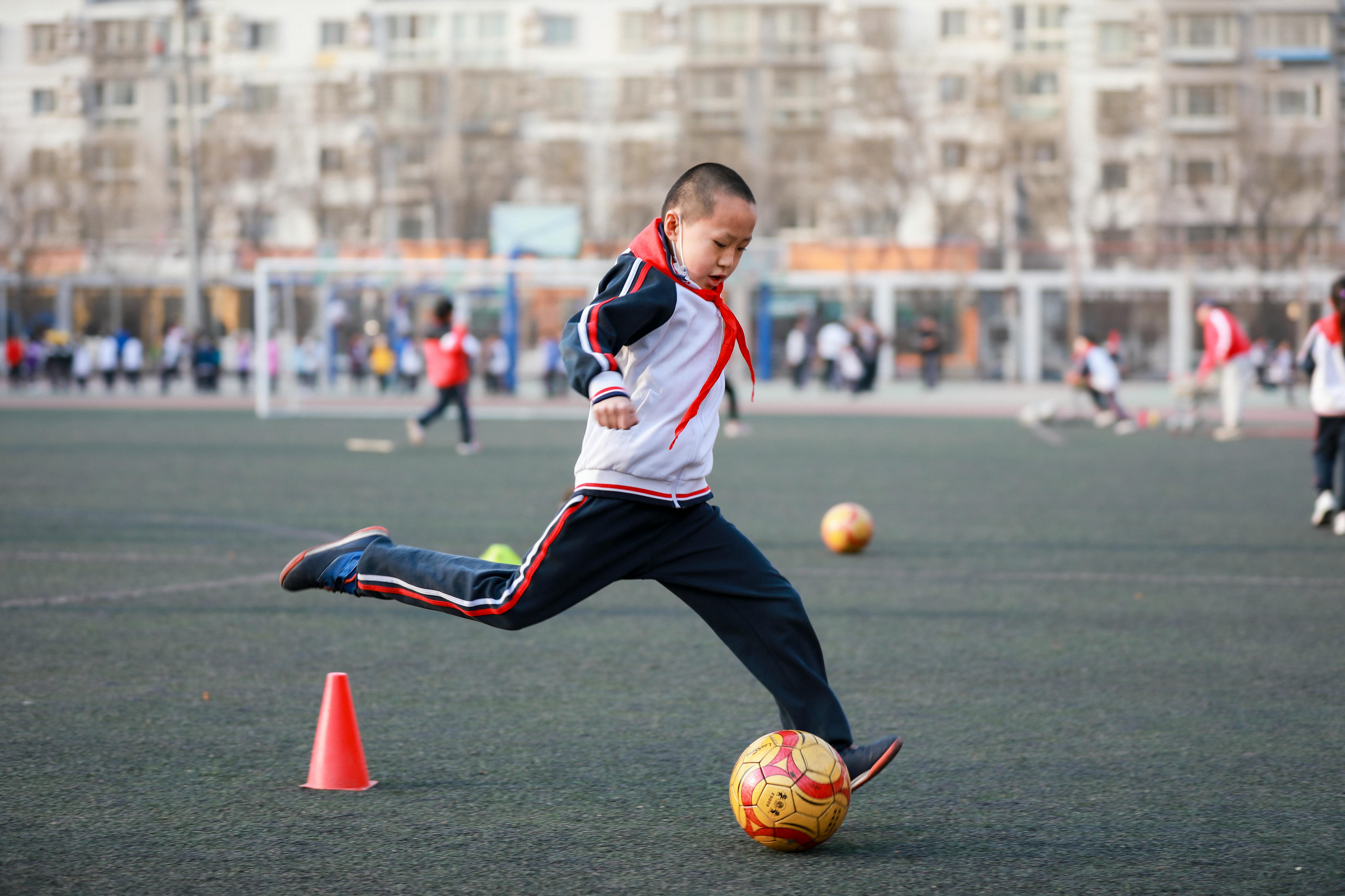 Little Boy Playing Football on a Pavement · Free Stock Photo