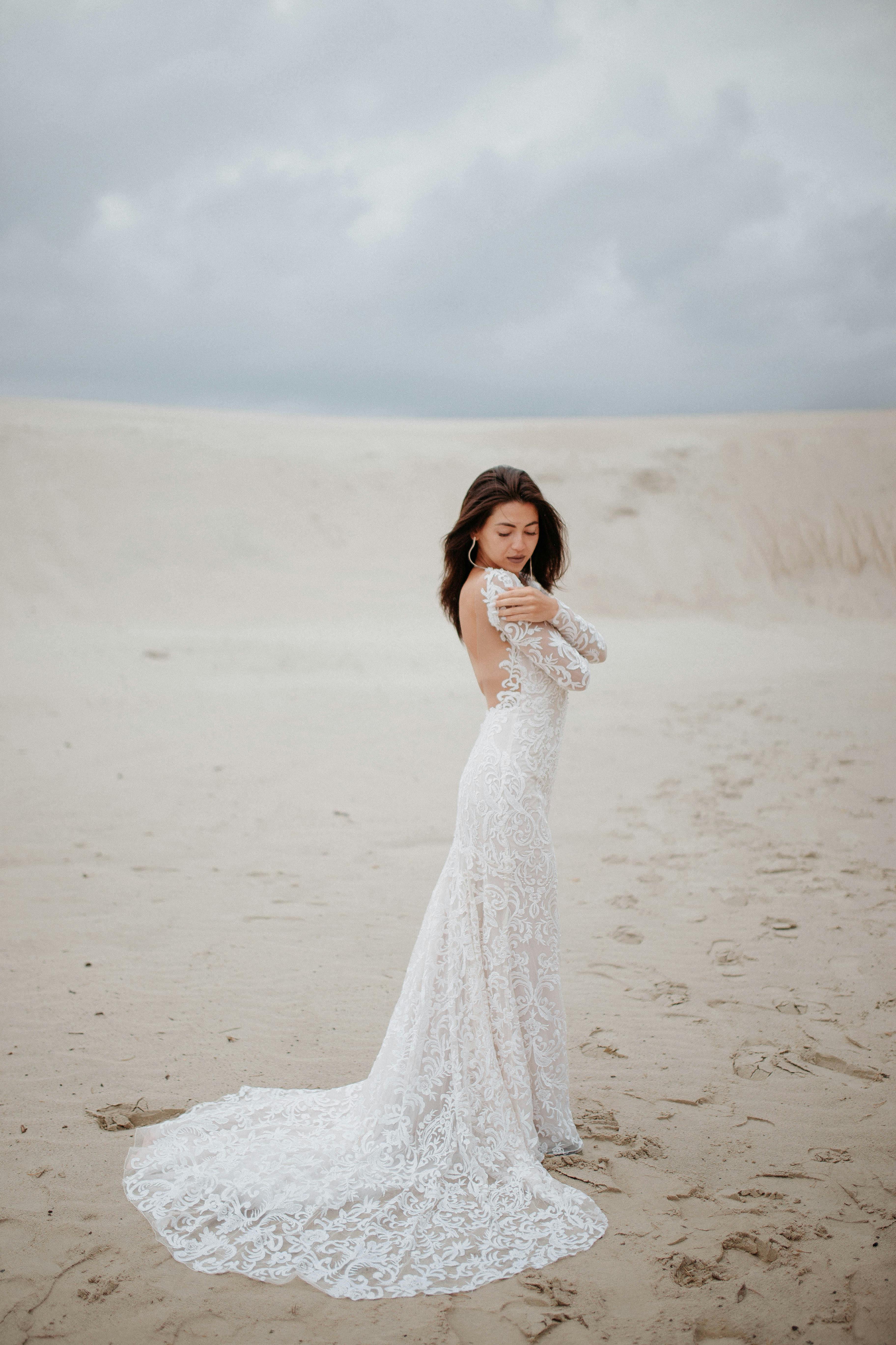 Bride in a Lace Wedding Dress Posing on the Beach · Free Stock Photo