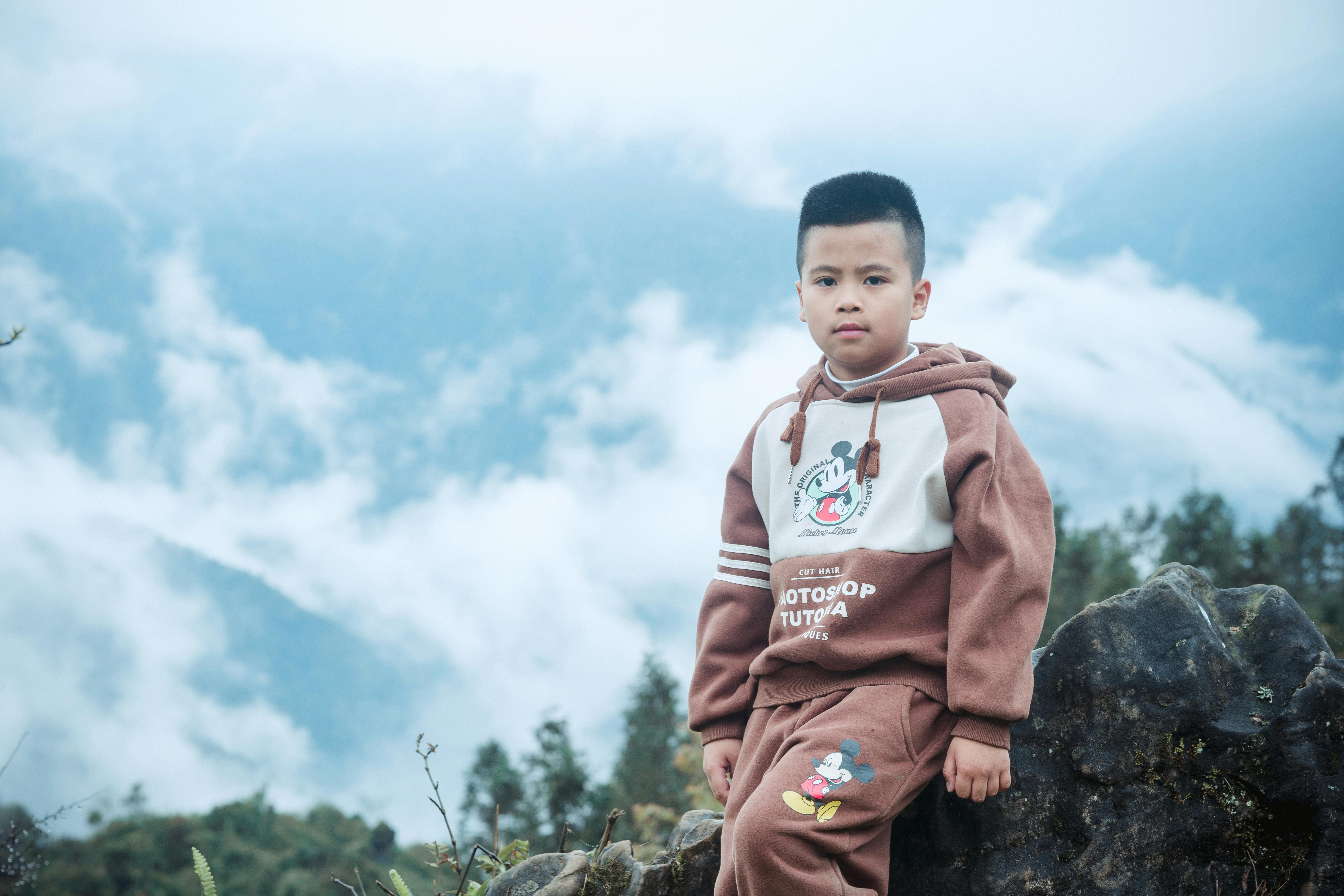 Photo of a Boy Wearing Overalls Leaning against a Rock · Free Stock Photo