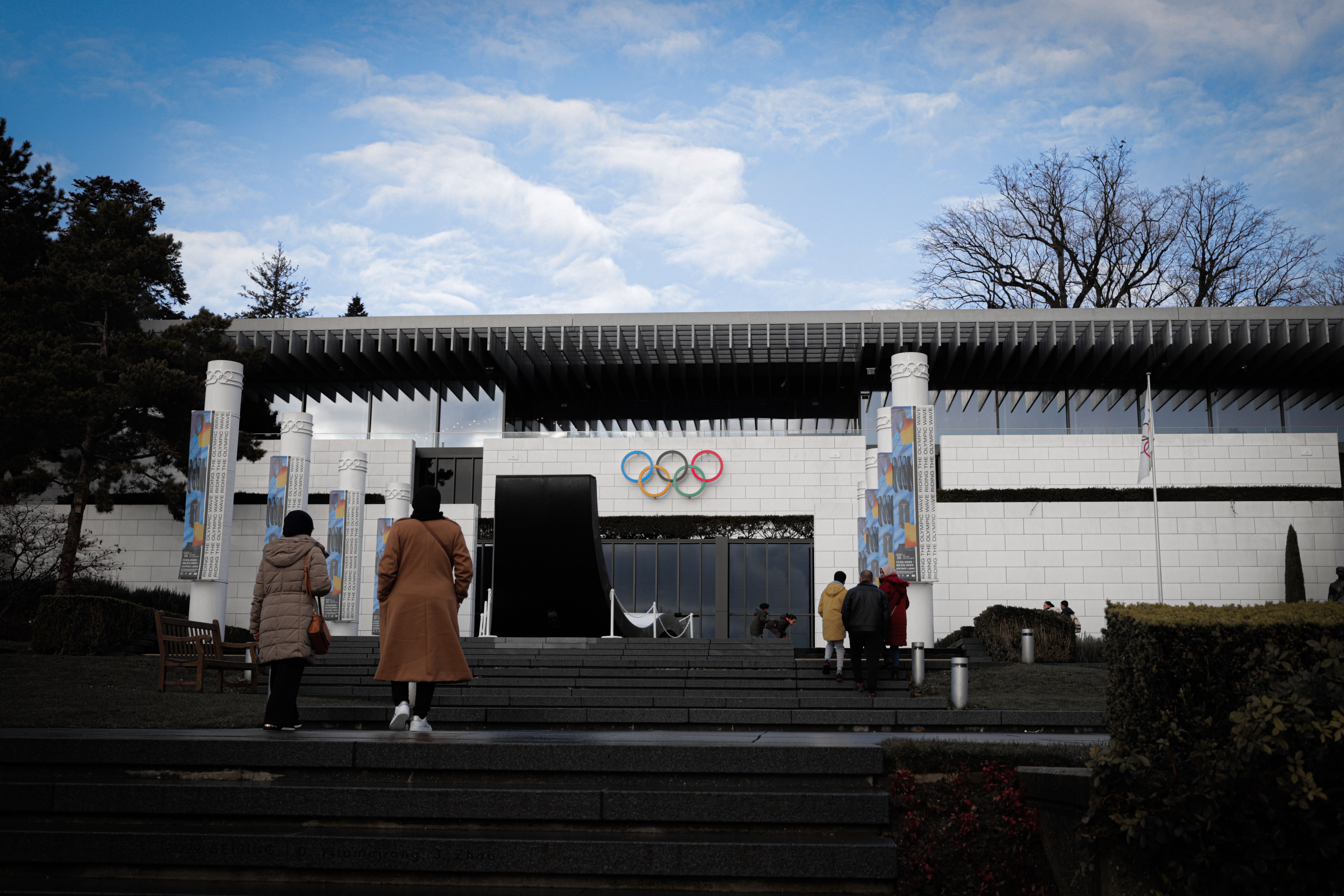 People walk past the entrance to the olympic building · Free Stock Photo