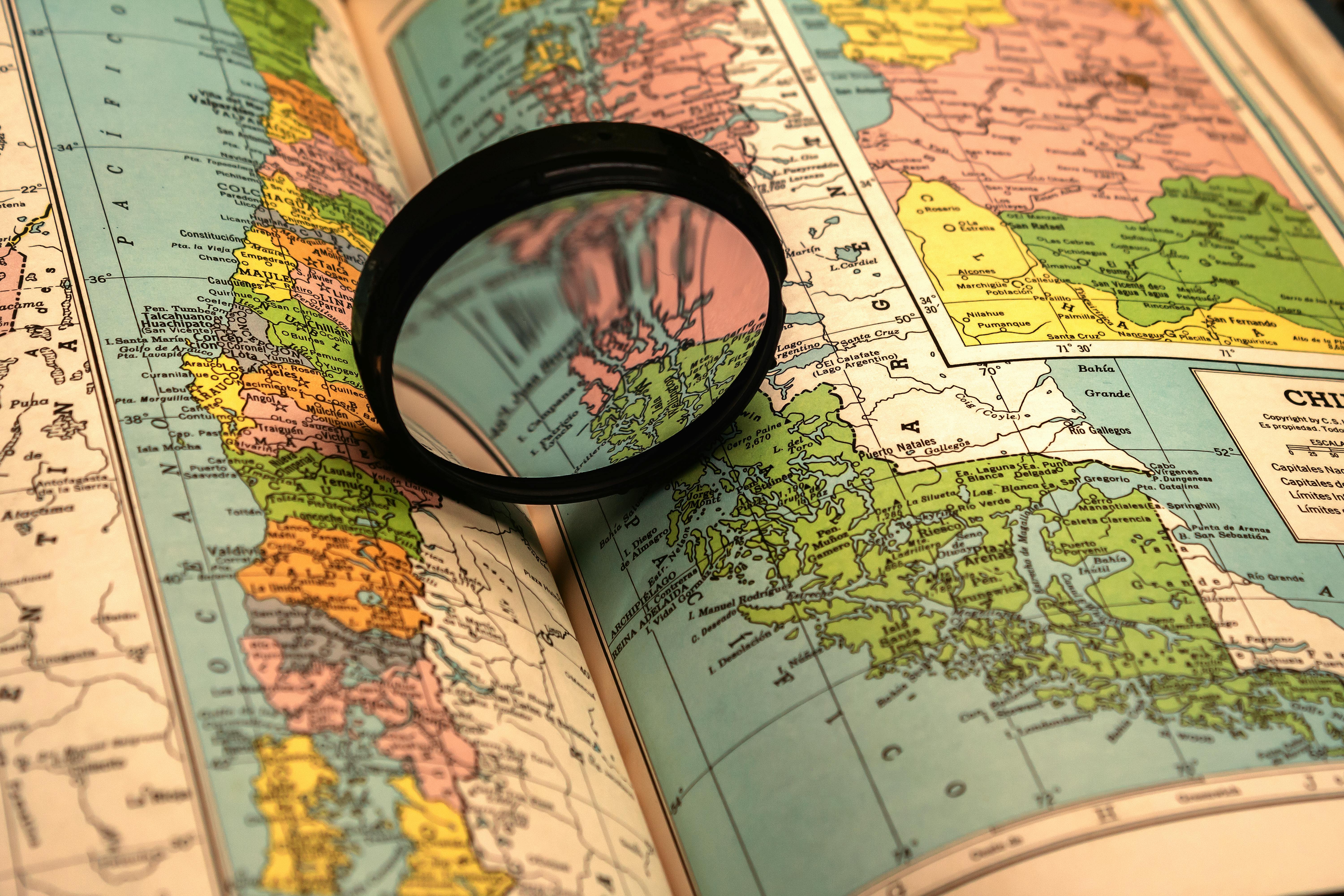 Close-up of a Magnifying Glass Lying on an Opened Book with a Map ...