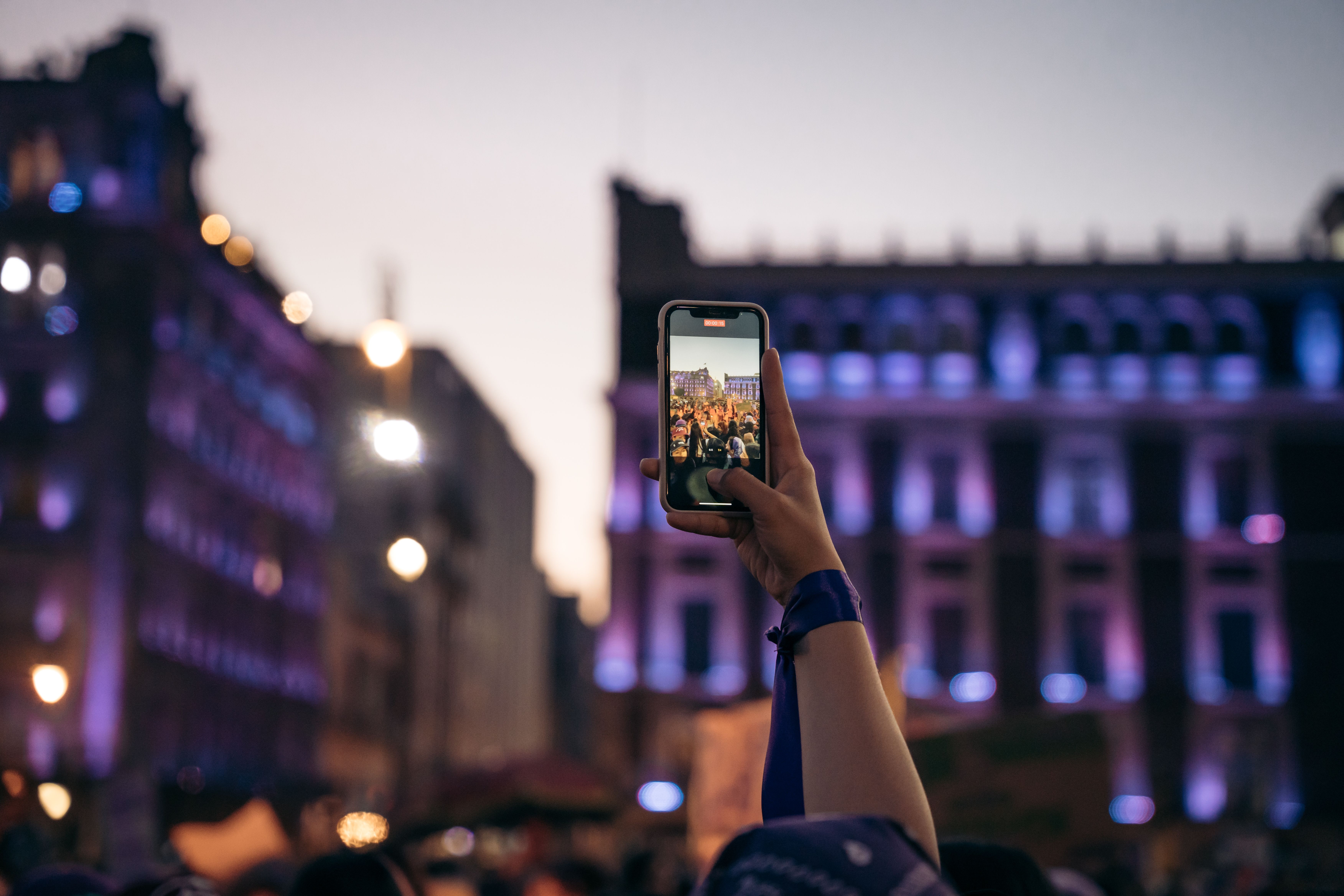 Violet Illuminated Buildings at Dusk, and a Person Photographing Crowd ...
