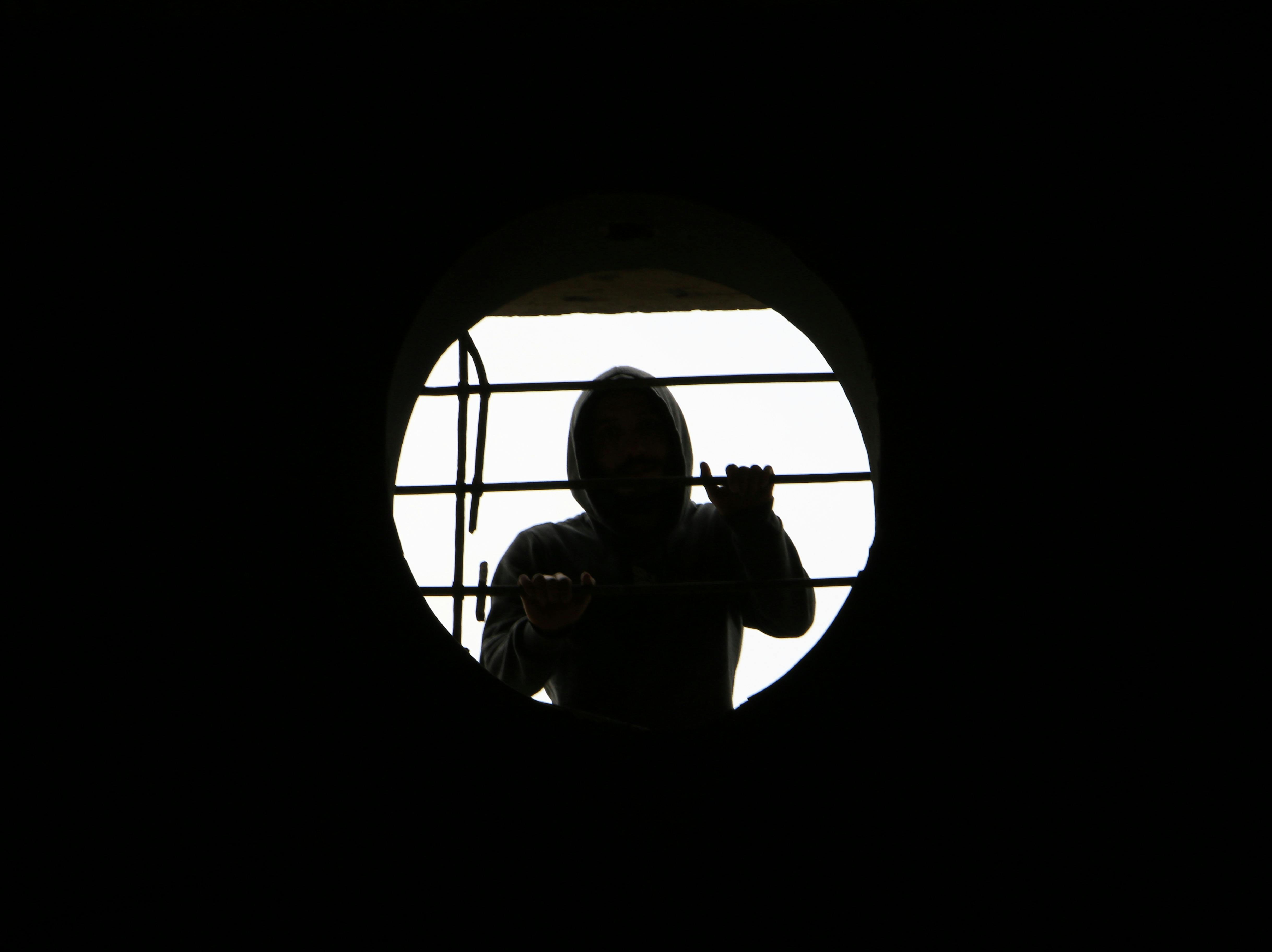 Silhouette of Person Standing in Round Barred Window · Free Stock Photo