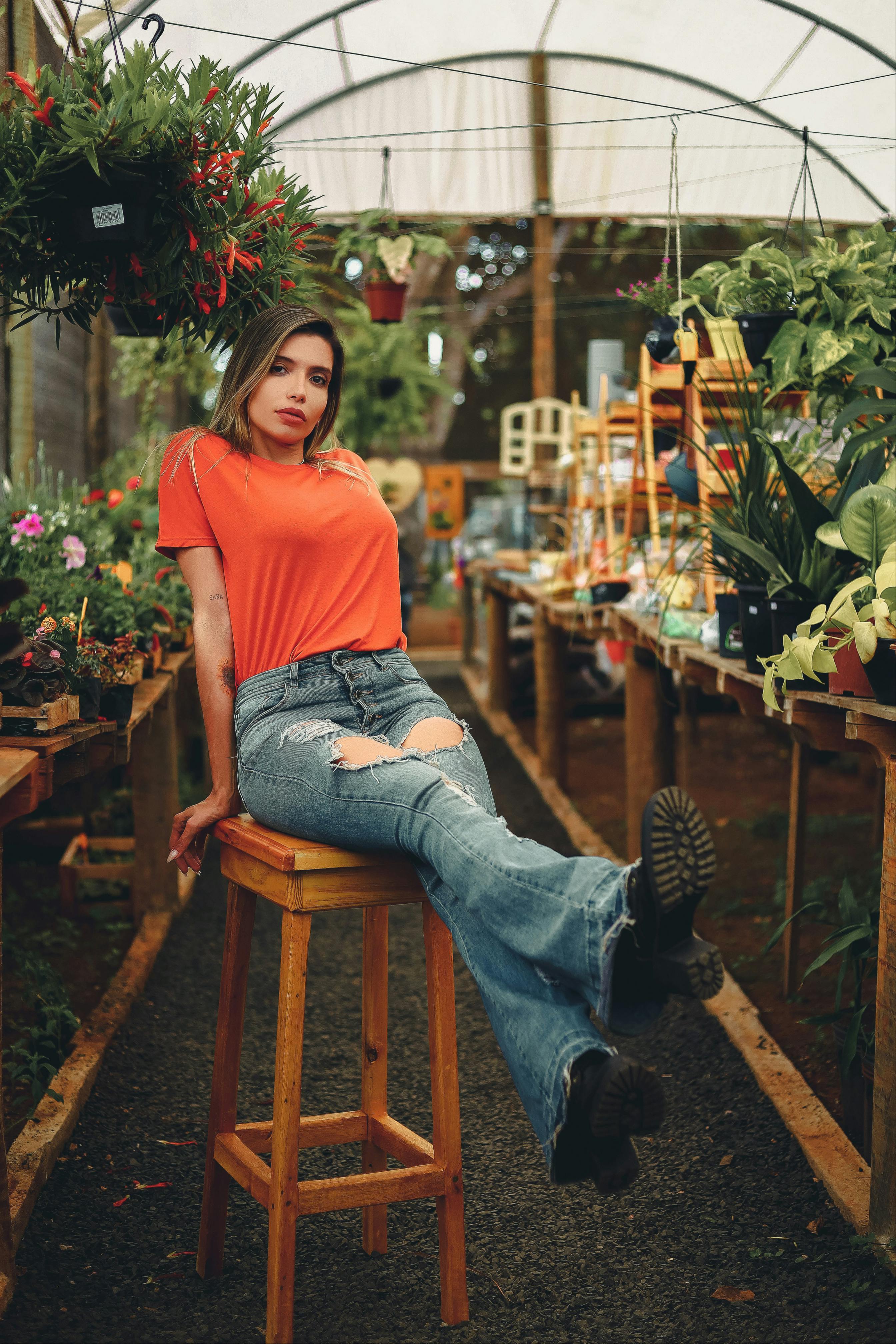 Young Woman Sitting on a Stool in a Greenhouse · Free Stock Photo