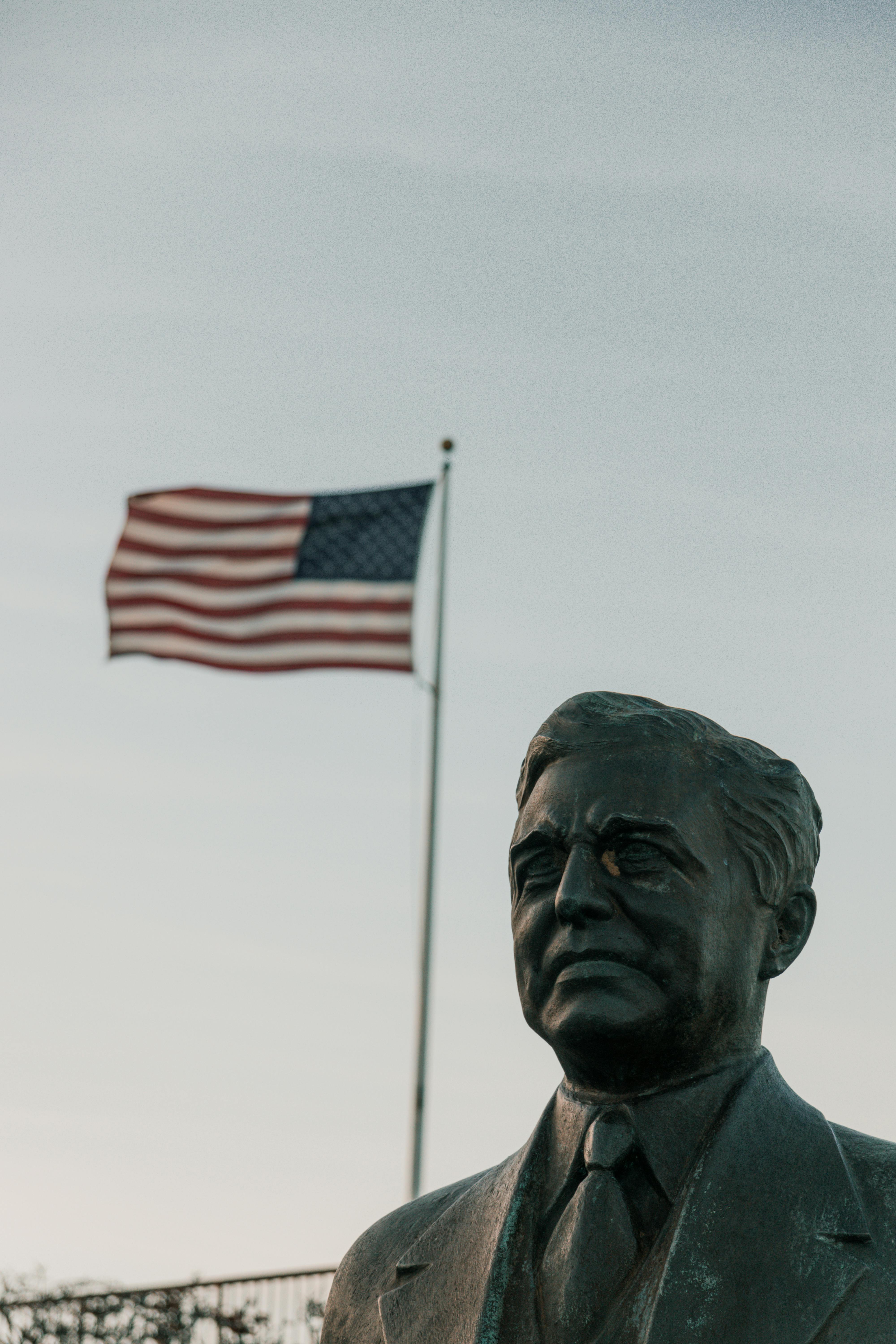 Man Face Sculpture and American Flag behind · Free Stock Photo